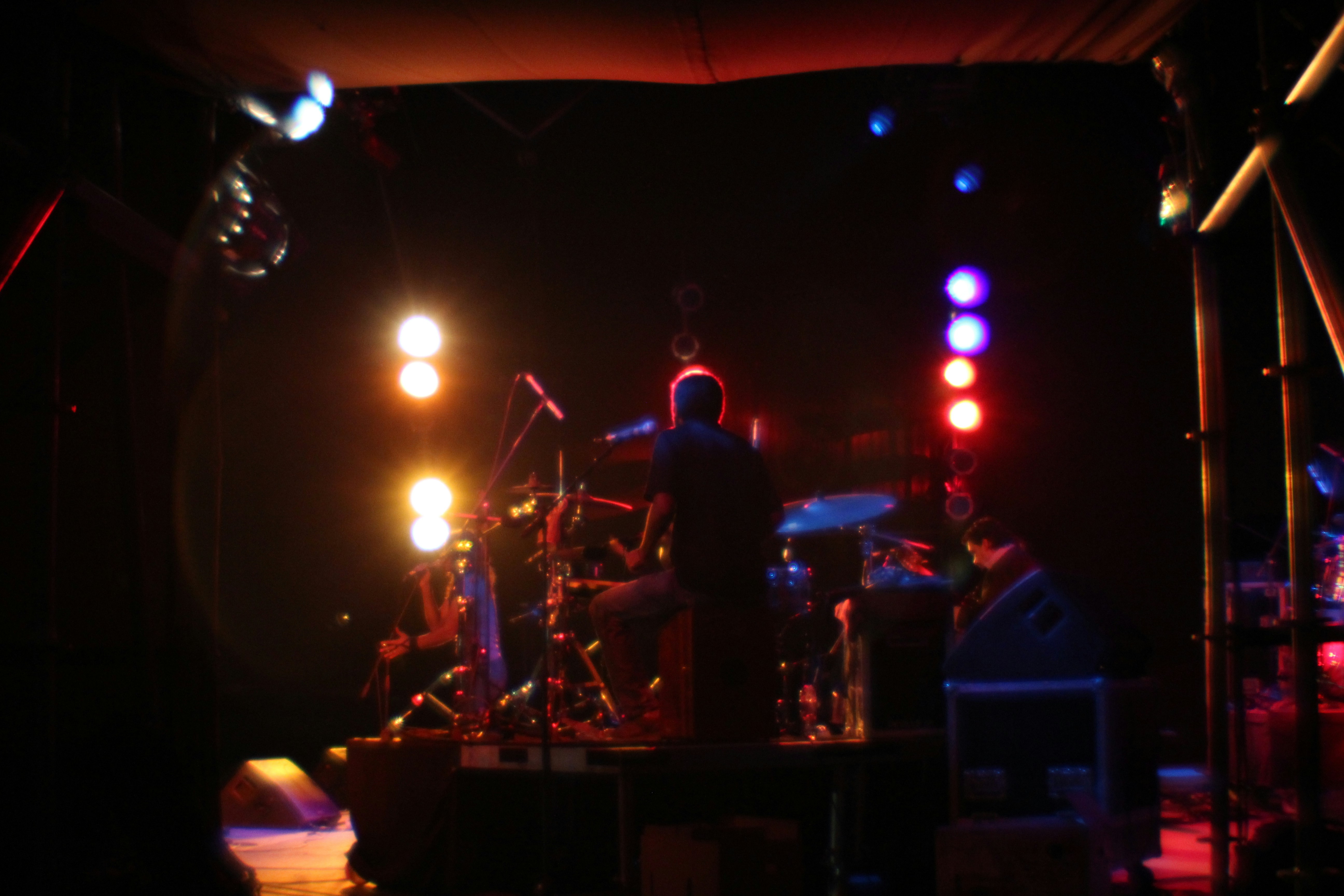 Backlit Silence: A Dim Stage Crescent of Color and Drumbeat
