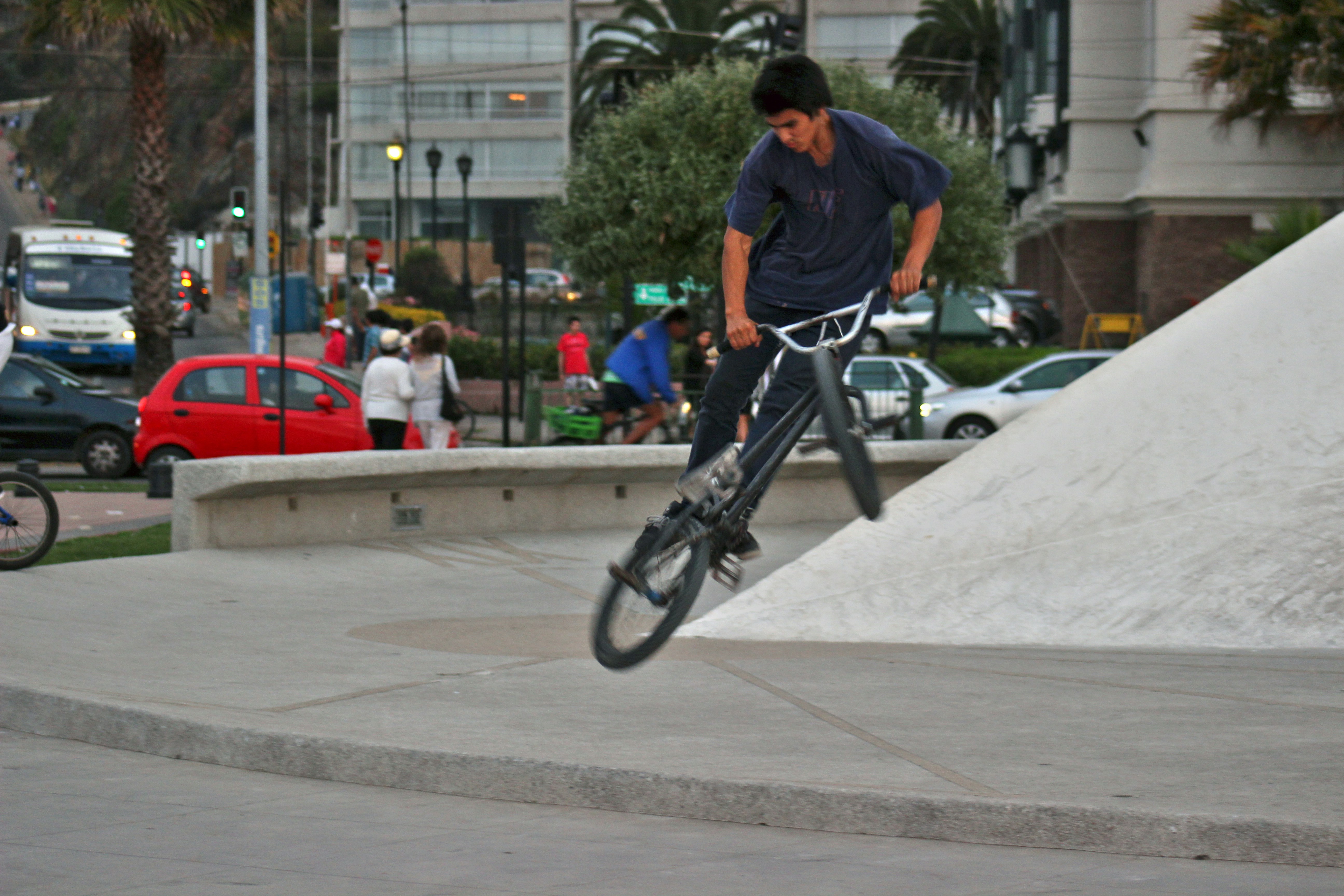 Biker lofts over concrete ramp in urban skate plaza