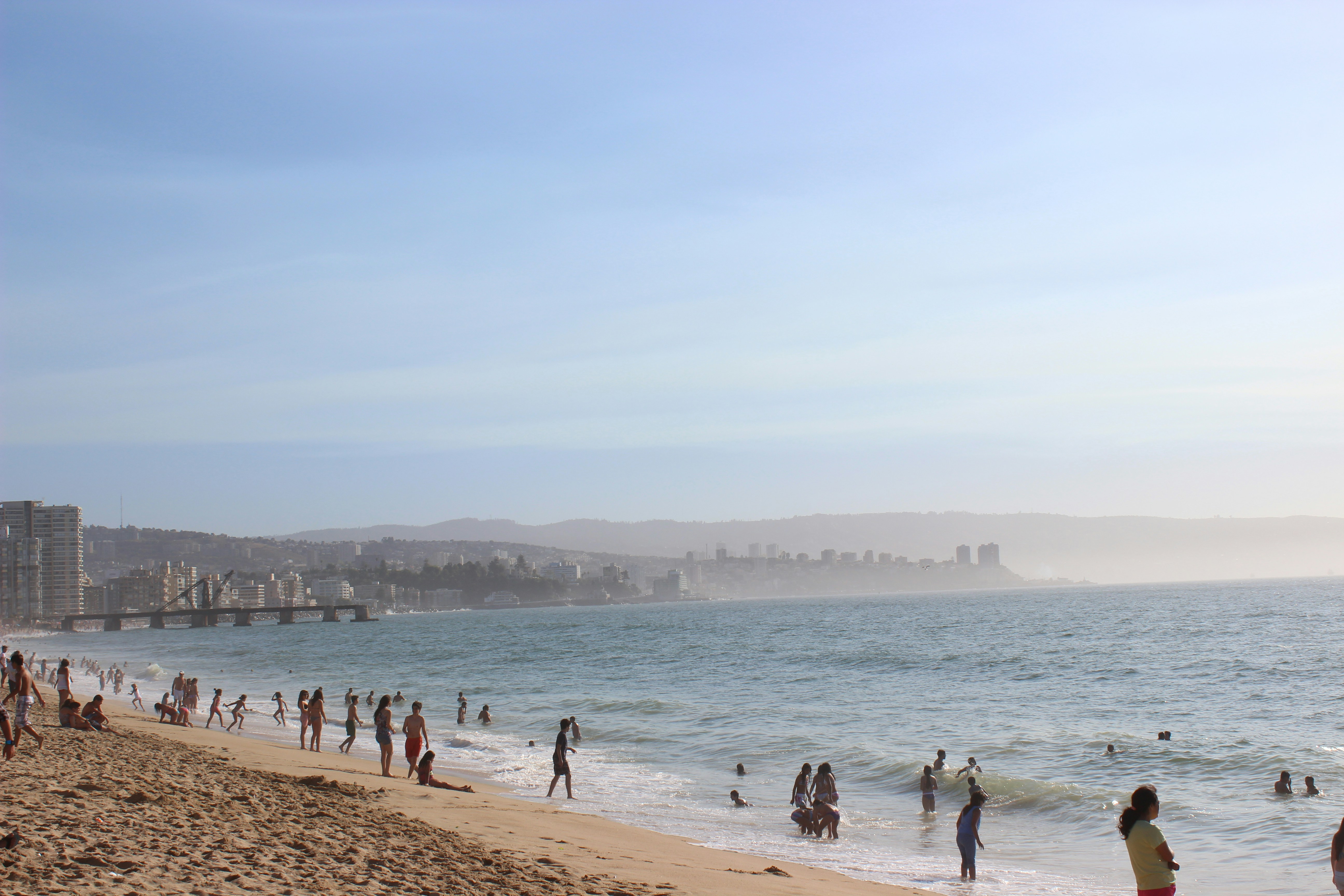 Sunlit Shoreline: Families and Waves Beneath a Wide Ocean Sky