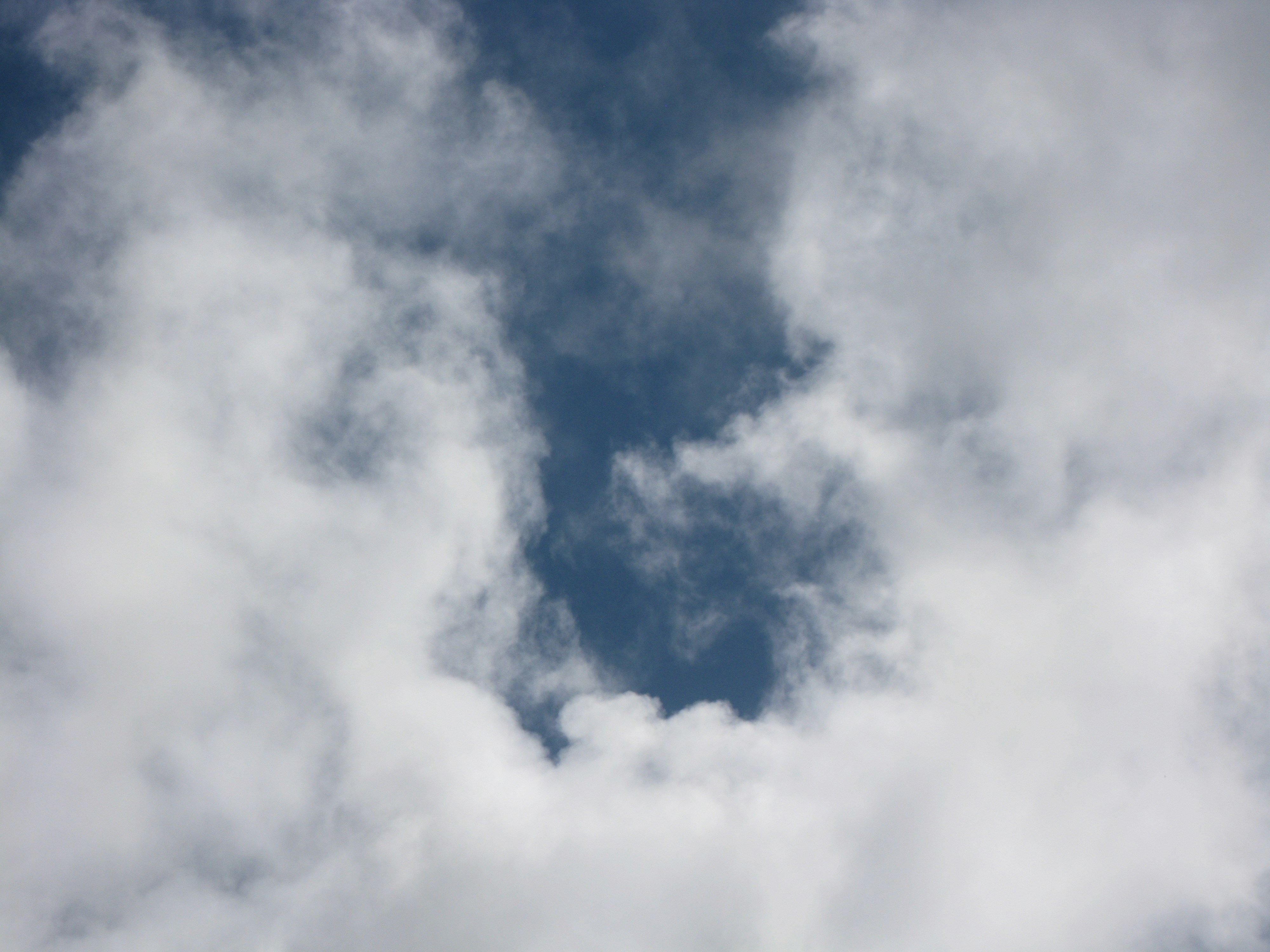 Open sky with fluffy white clouds breaking into blue, capturing a serene moment of daylight. The scene emphasizes expansive atmosphere and natural light without human elements.
