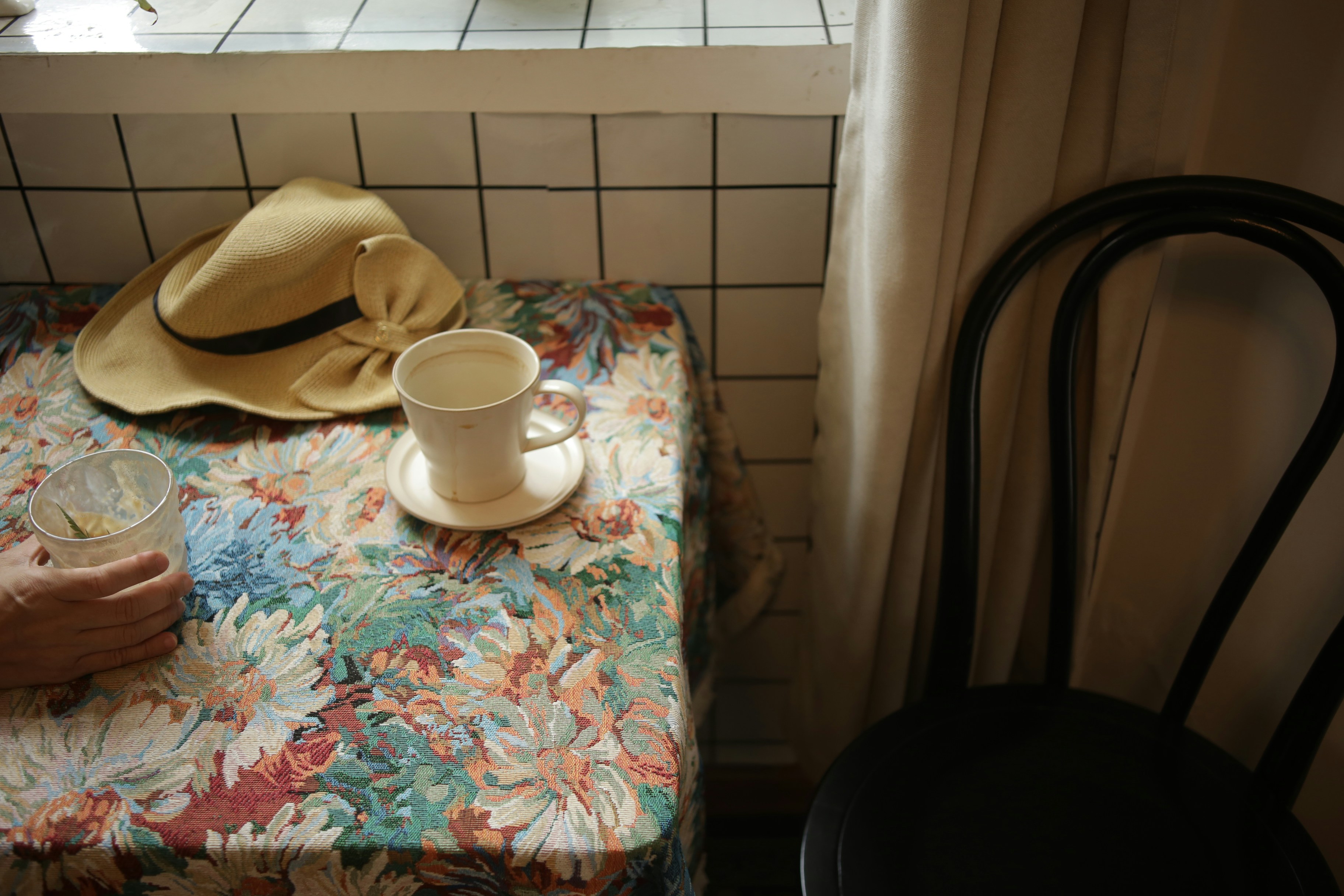 Sunlit Tabletop Moment: Hat, Cup, and Glass in Quiet Café Light
