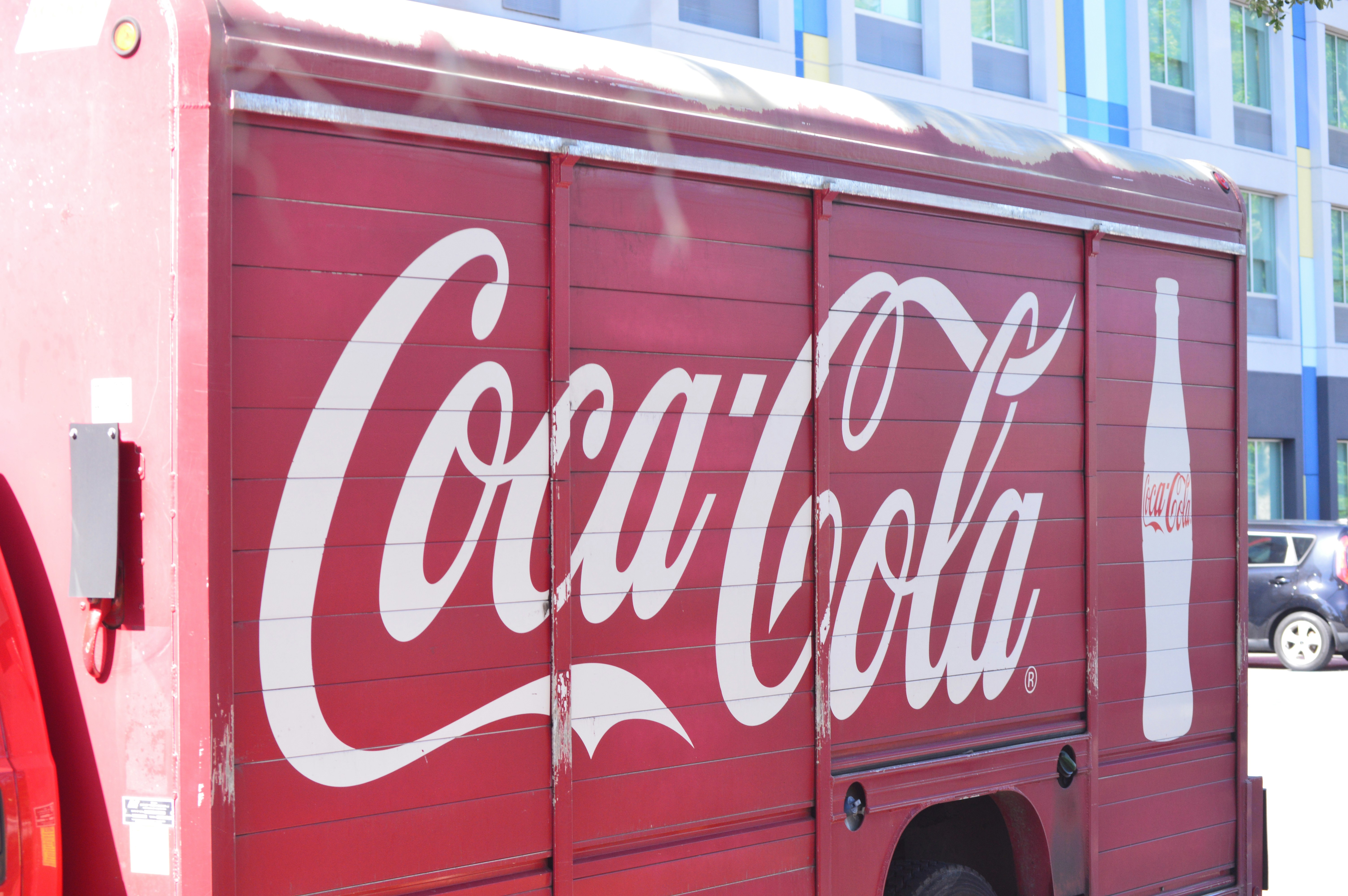 Crimson Beverage Carrier: A Coca-Cola Truck in Bright Urban Light