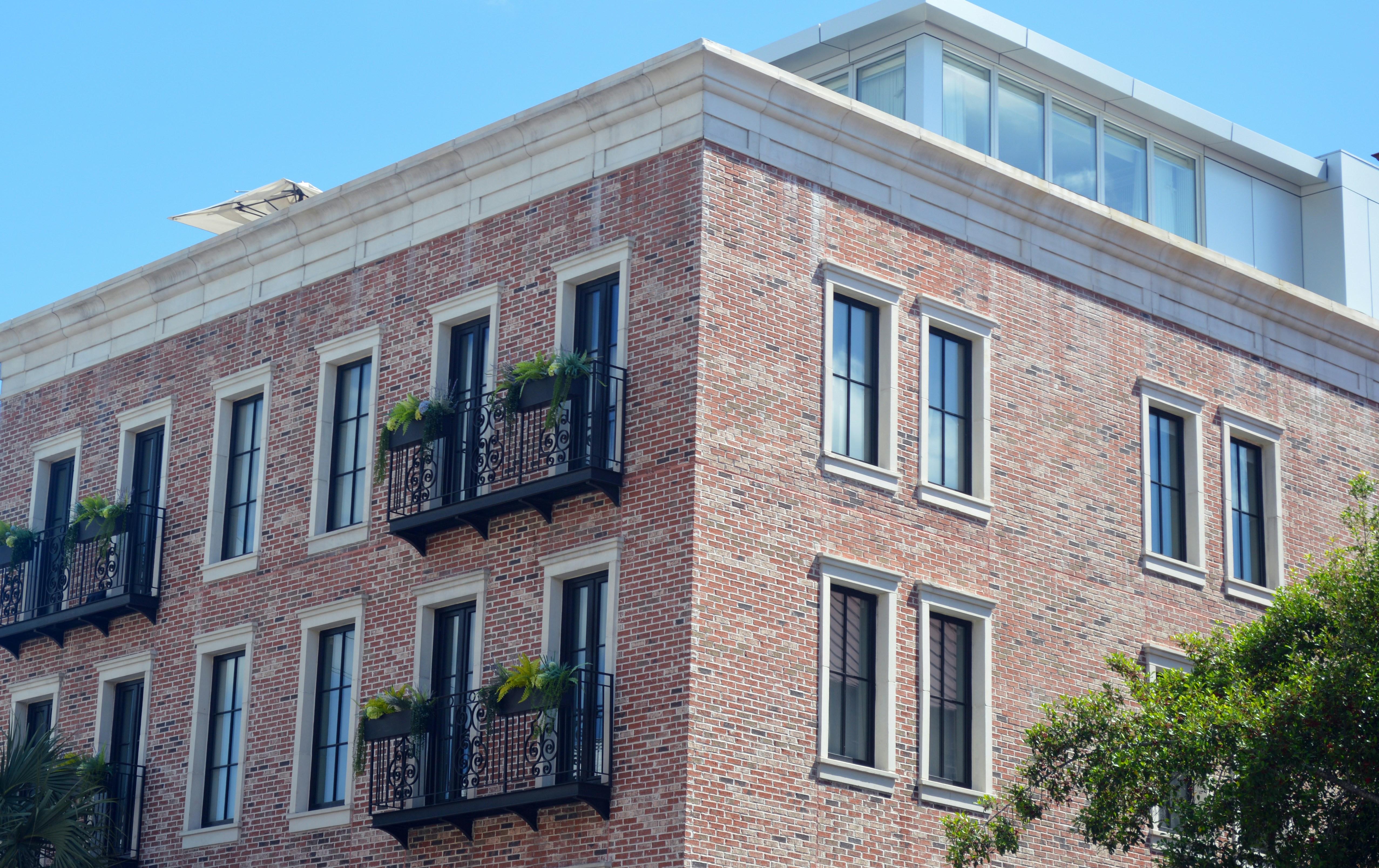 Brick Corner Oasis: Balcony Planters Framing a Neon Sky