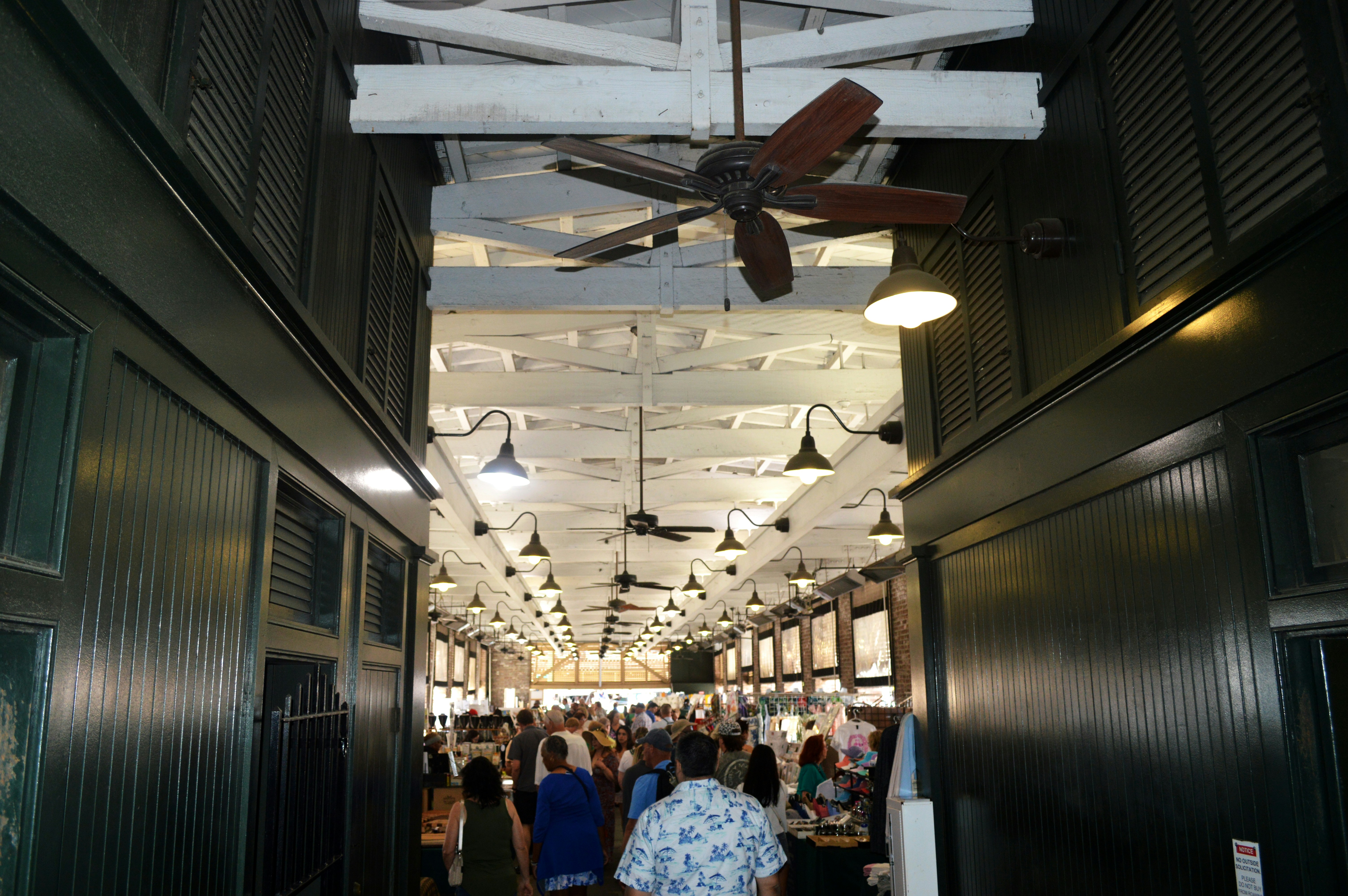Market Corridor: A Bazaar of Heads and Hats Under Ceiling Fans