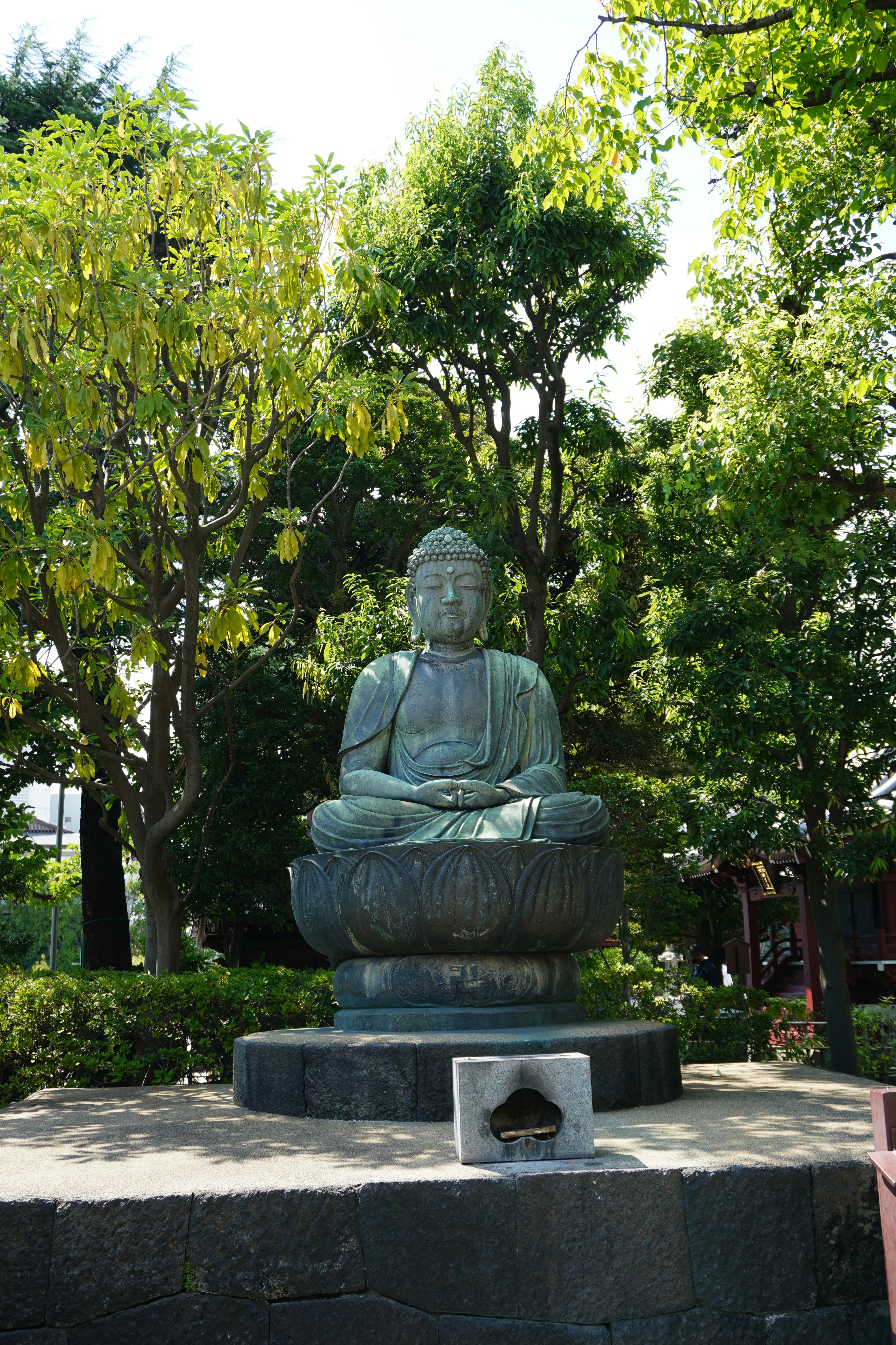 Meditative Iron Serene: A Buddha statue in sunlit temple garden