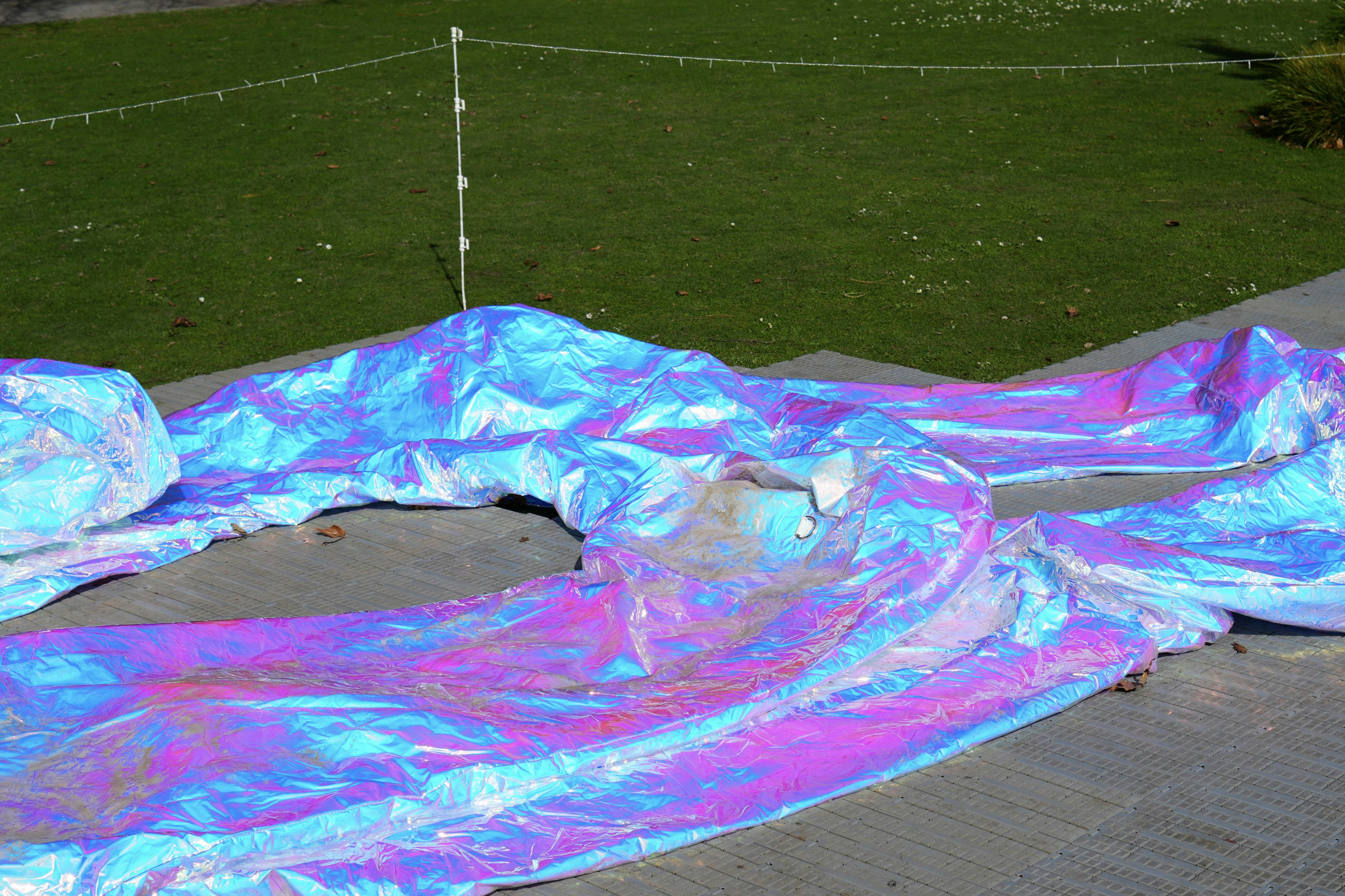 Iridescent tarp waves on a grassy edge