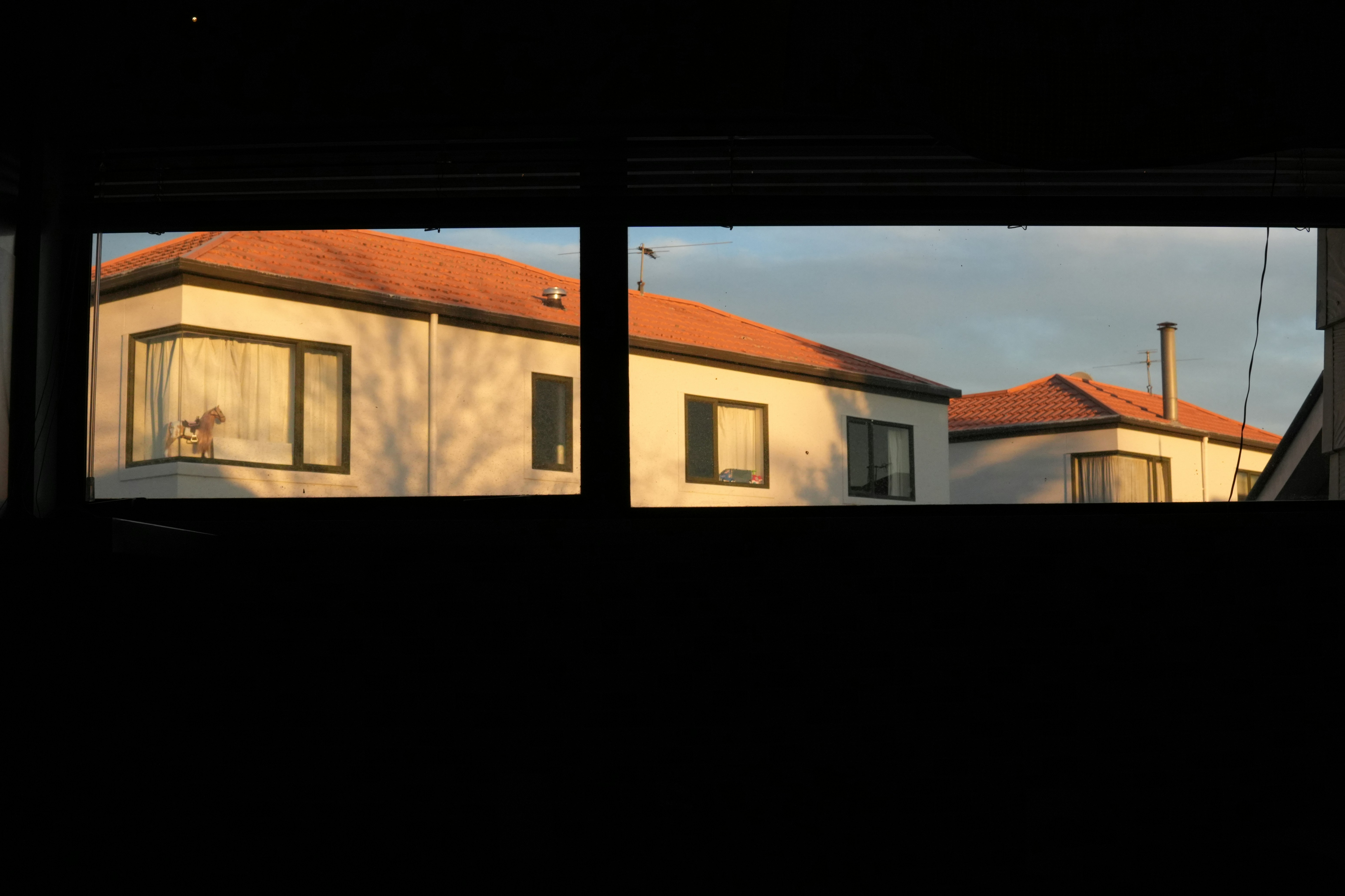 Sunlit Row of Townhouses Framed by a Dark Window