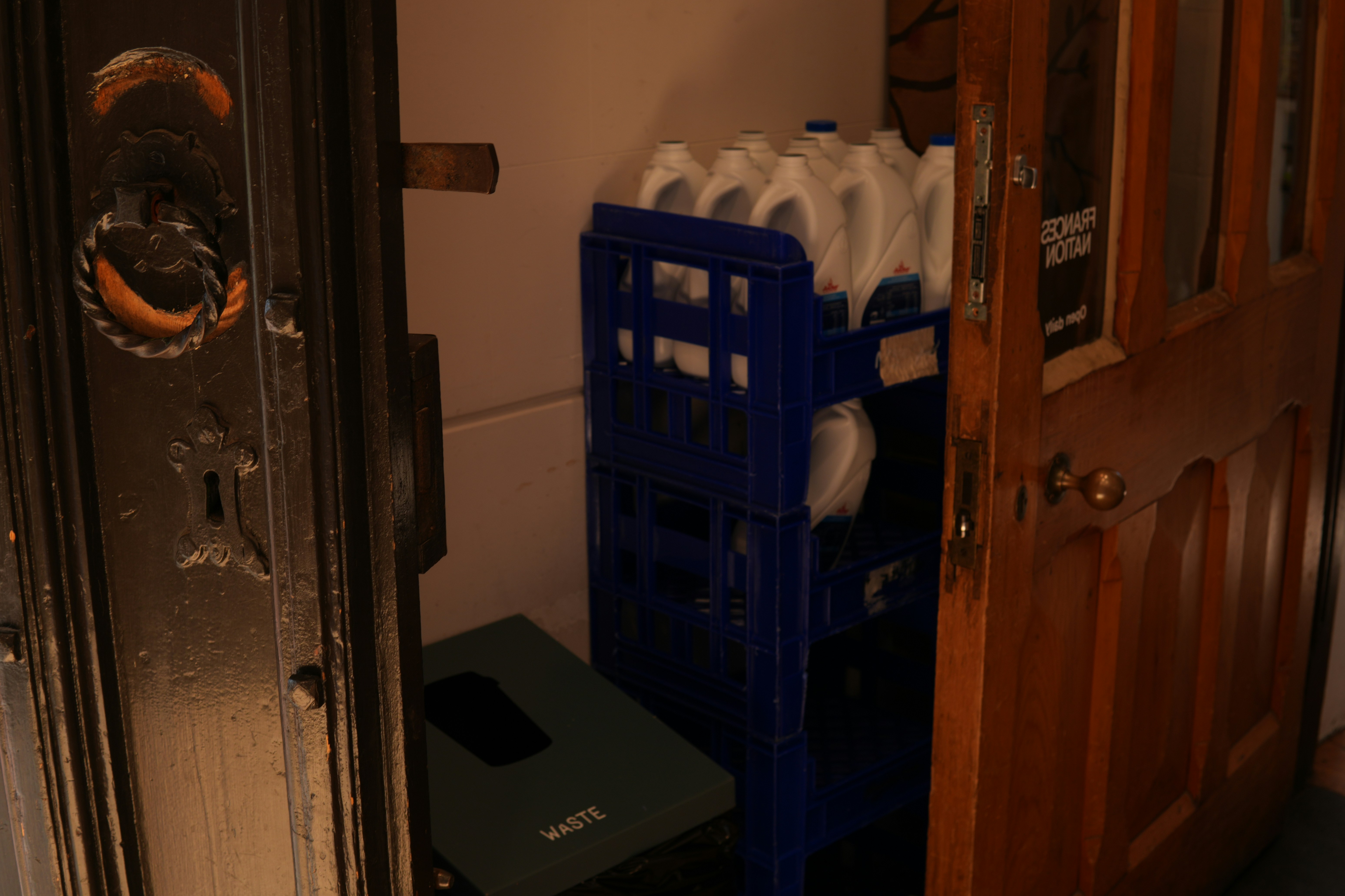 Doorway to a Utility Nook: Milk Jugs and Crate in Dim Hallway