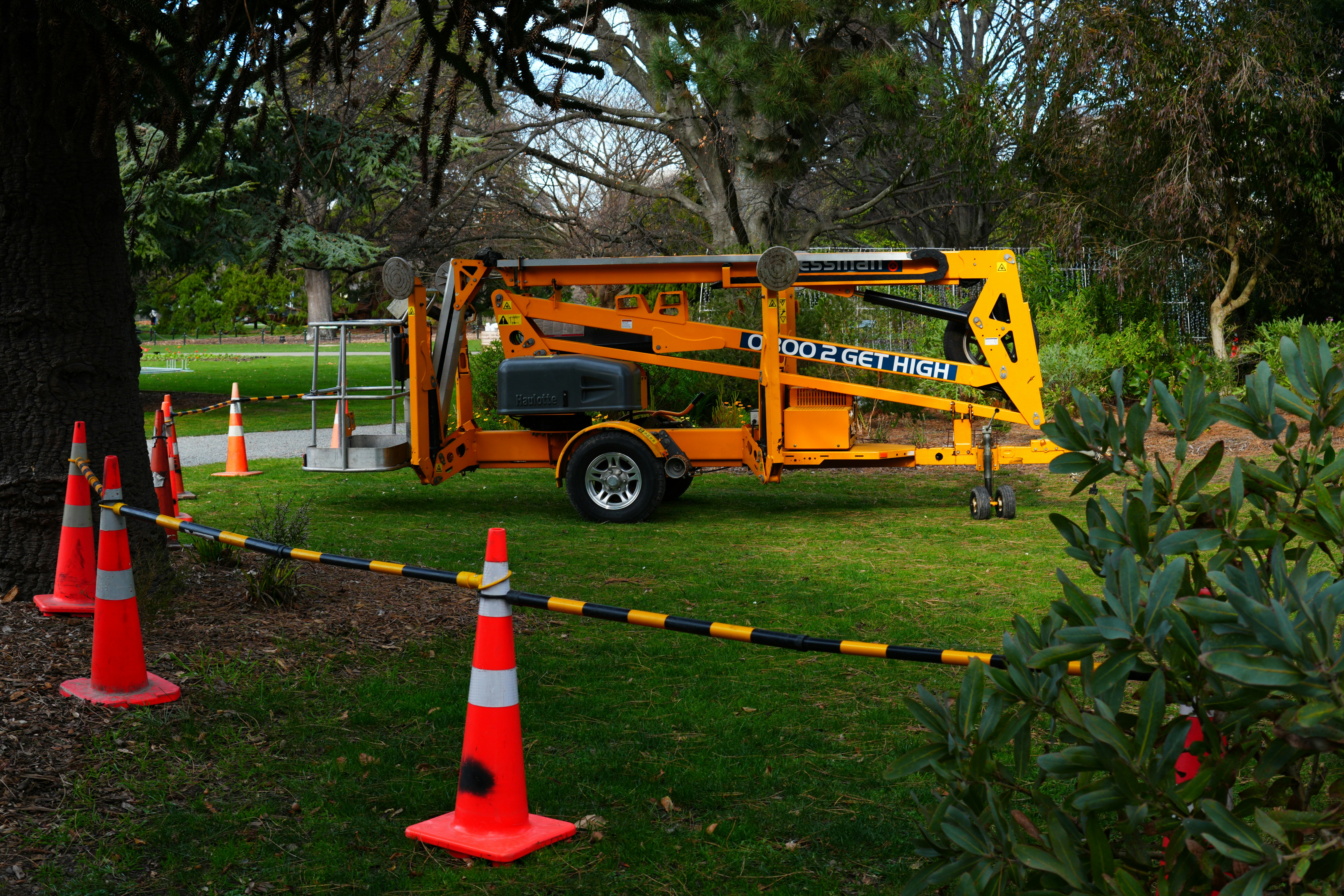 Orange Aerial Lift on a Green Patch: A Construction Scene in a Park
