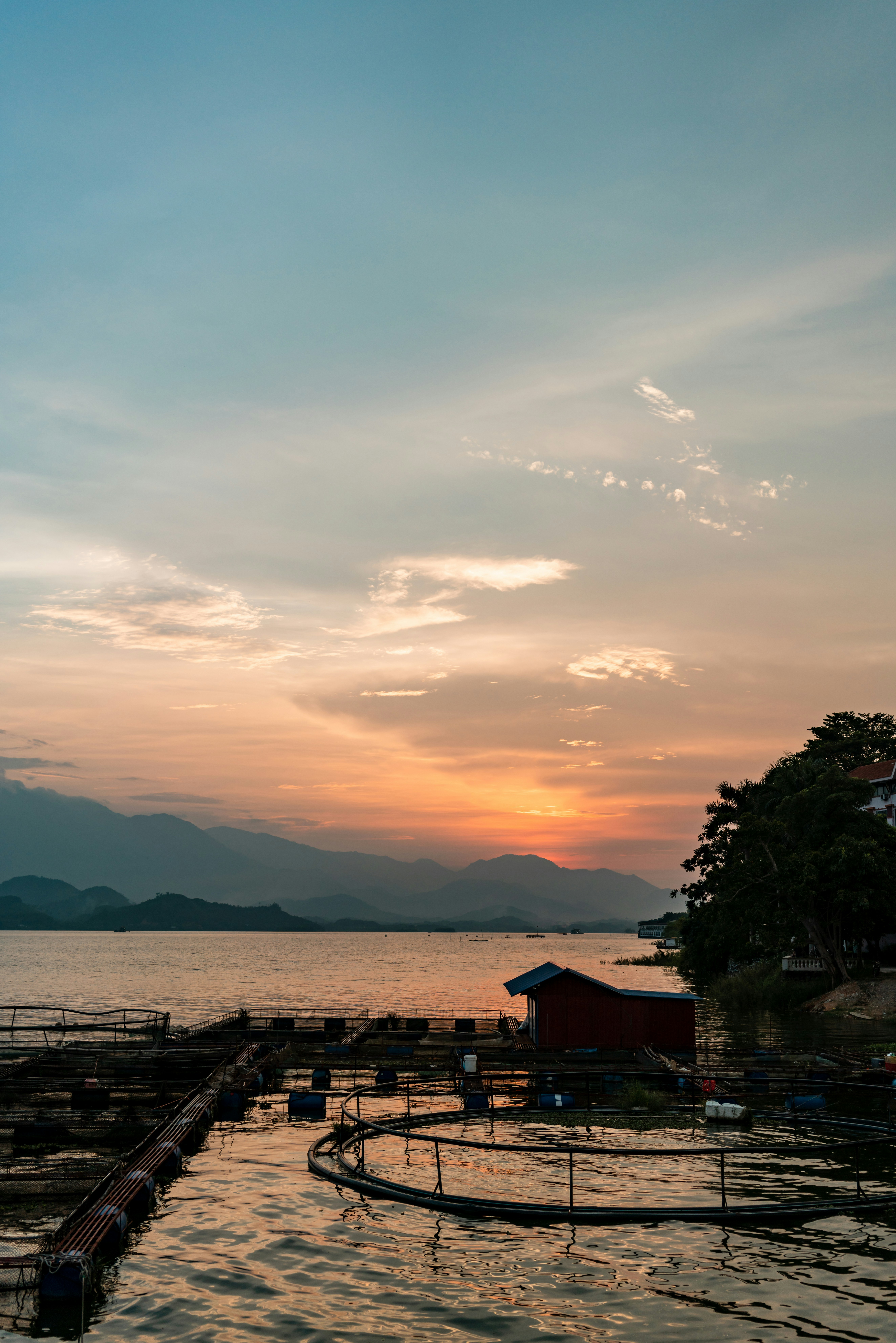 Sunset Over Quiet Waters: Docks, Red Boathouse, and Distant Mist