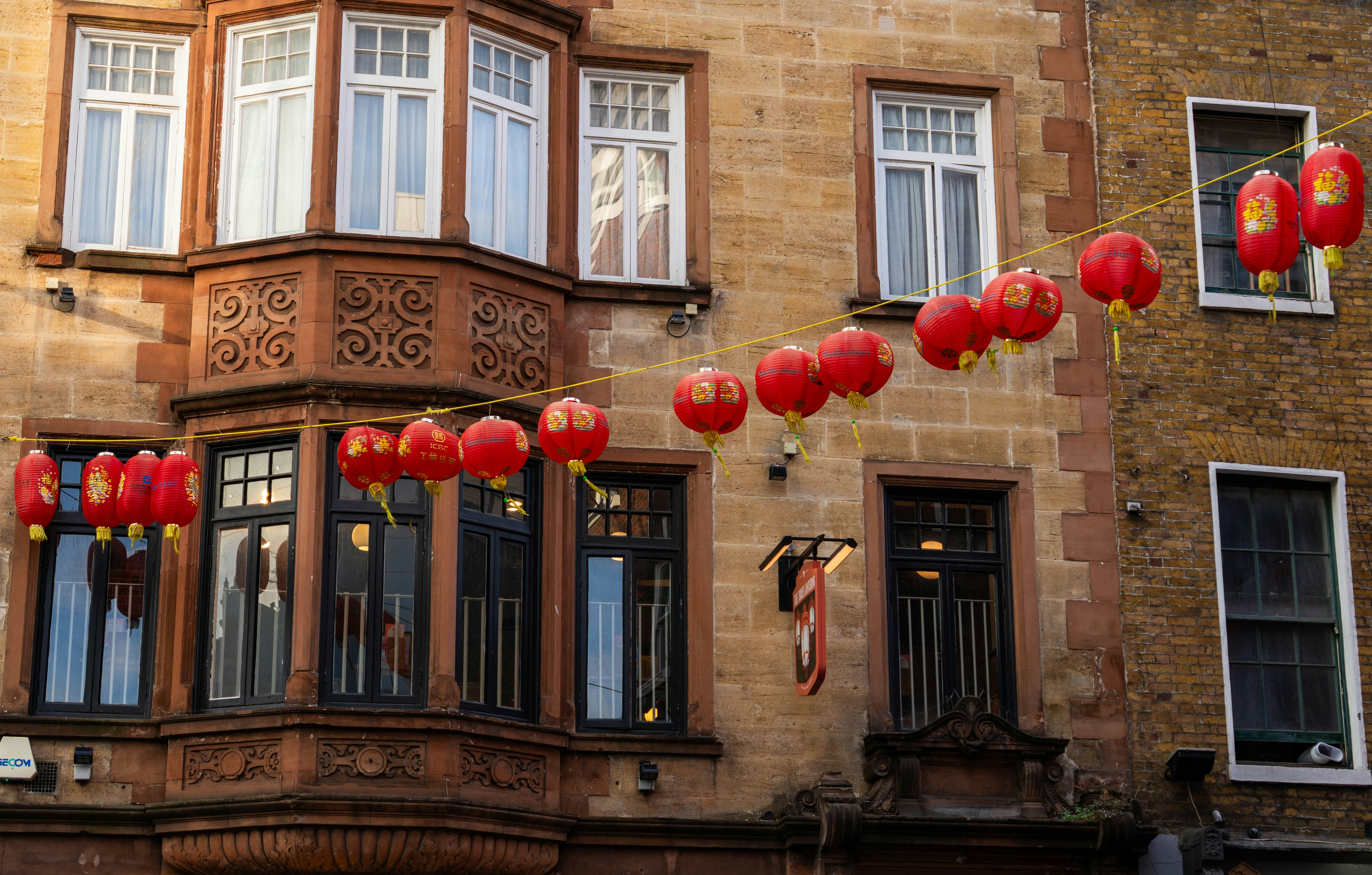 Red Chinese lanterns hanging across the facade of a historic building in London Chinatown.