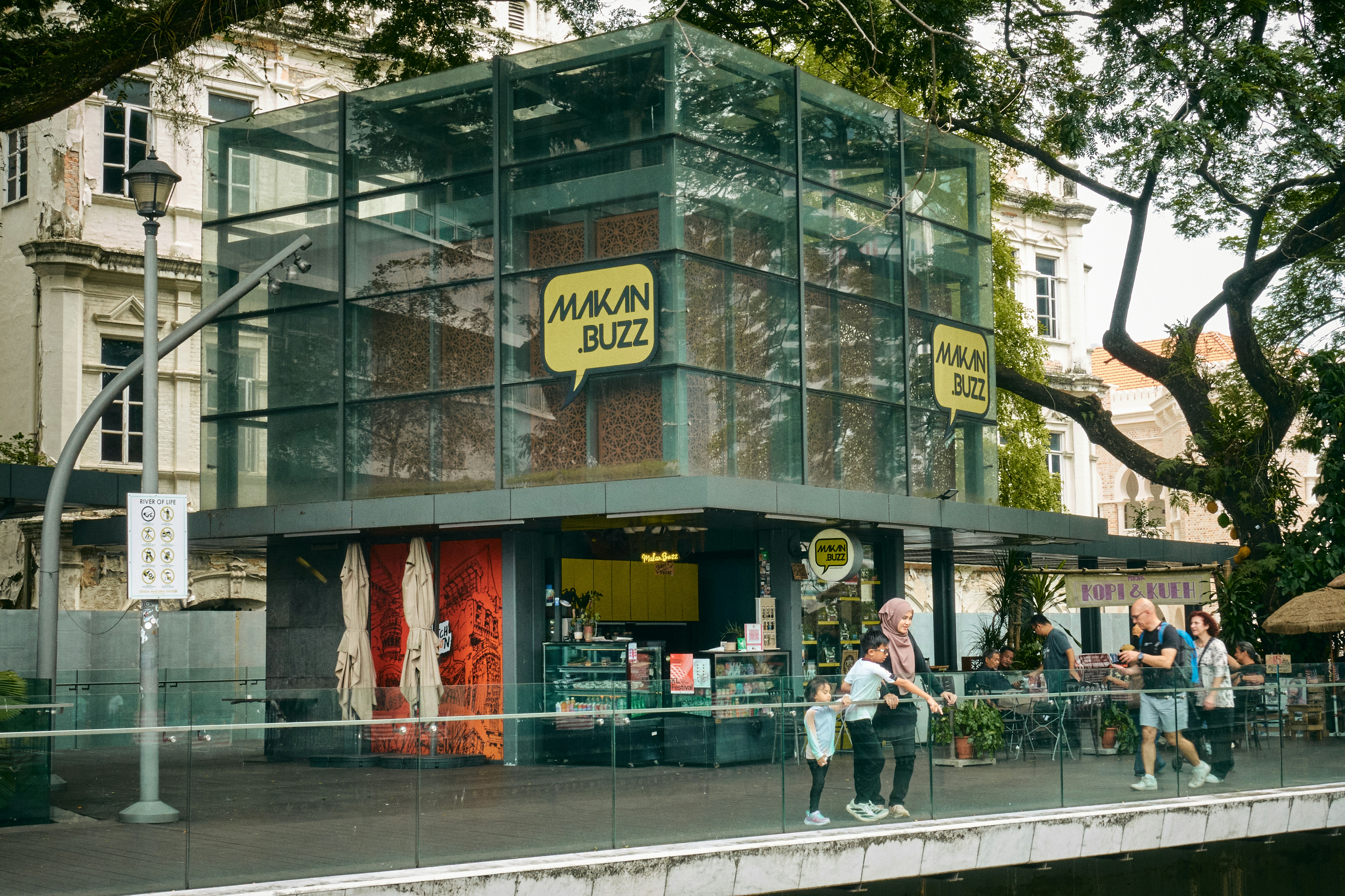GlassBox Café by the river: Mikan Buzz storefront with vivid yellow logos