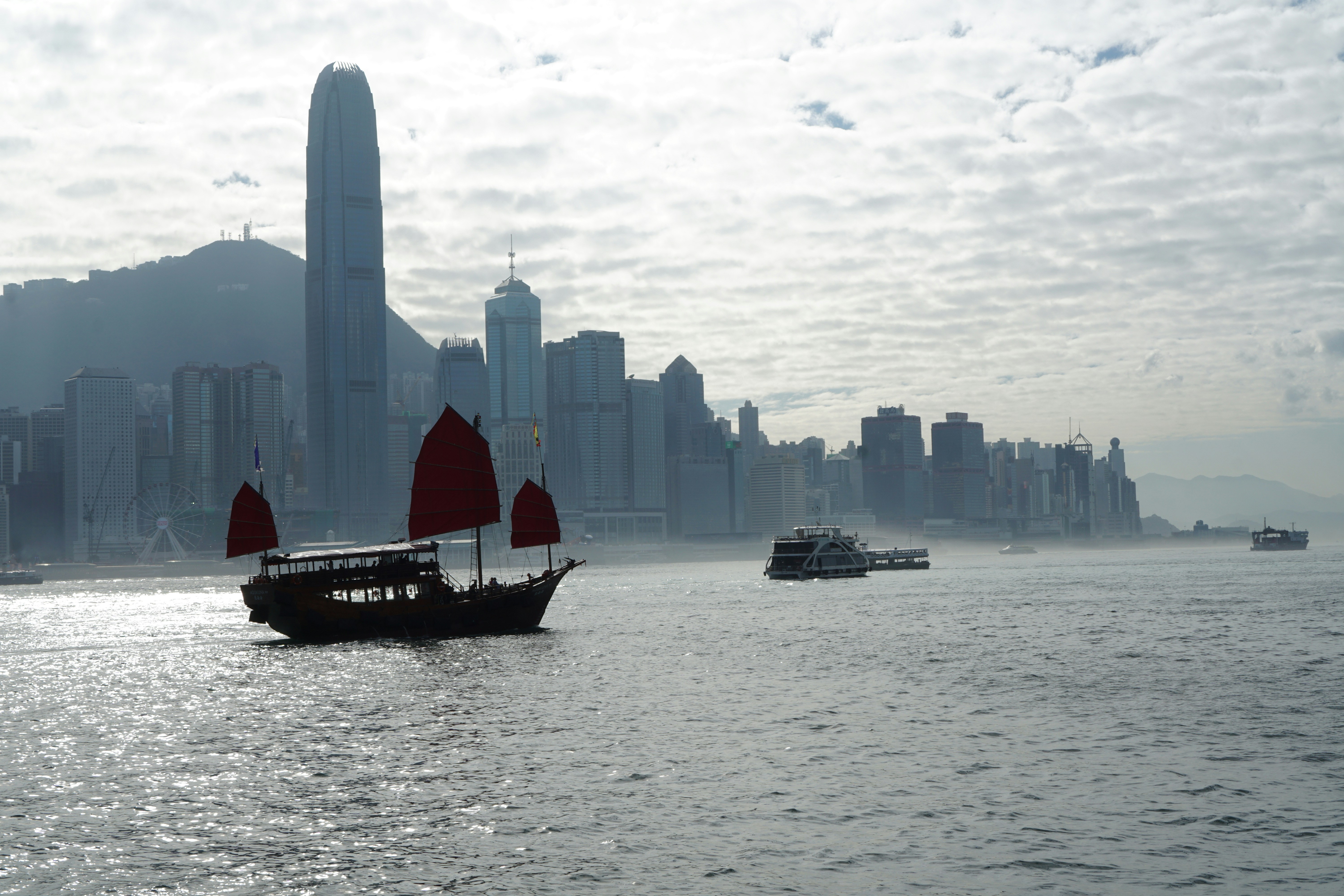 Red-sailed Junk Boat against a City Skyline
