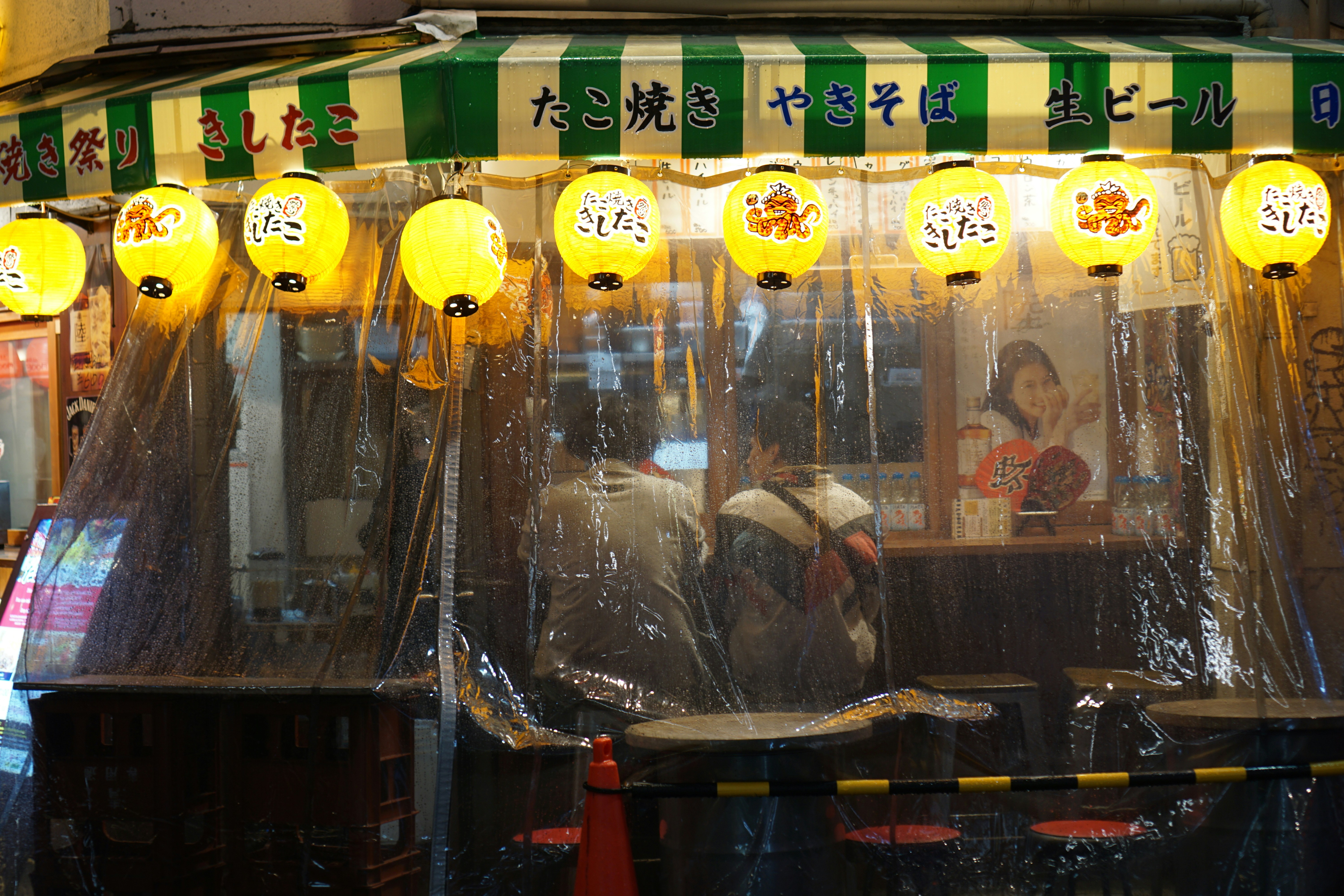 Lantern-lit stalls and translucent canopy at a nighttime Japanese street food stall