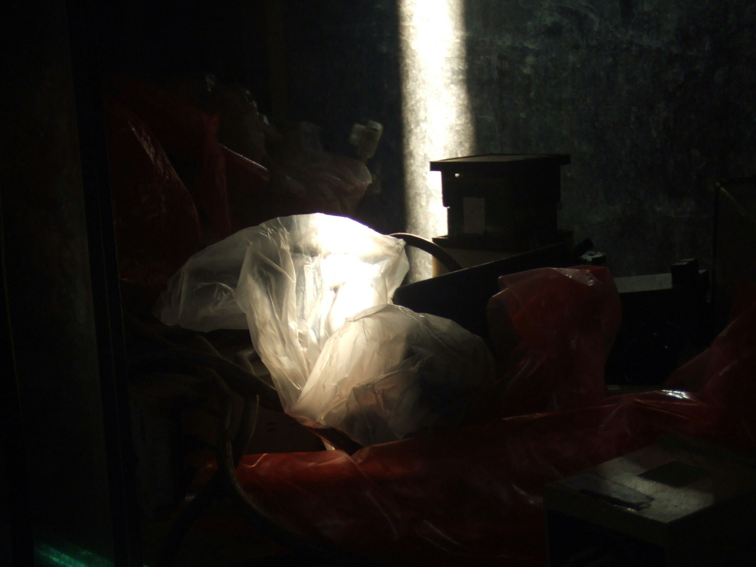 Industrial shadows: a dimly lit scene with plastic bags and machinery