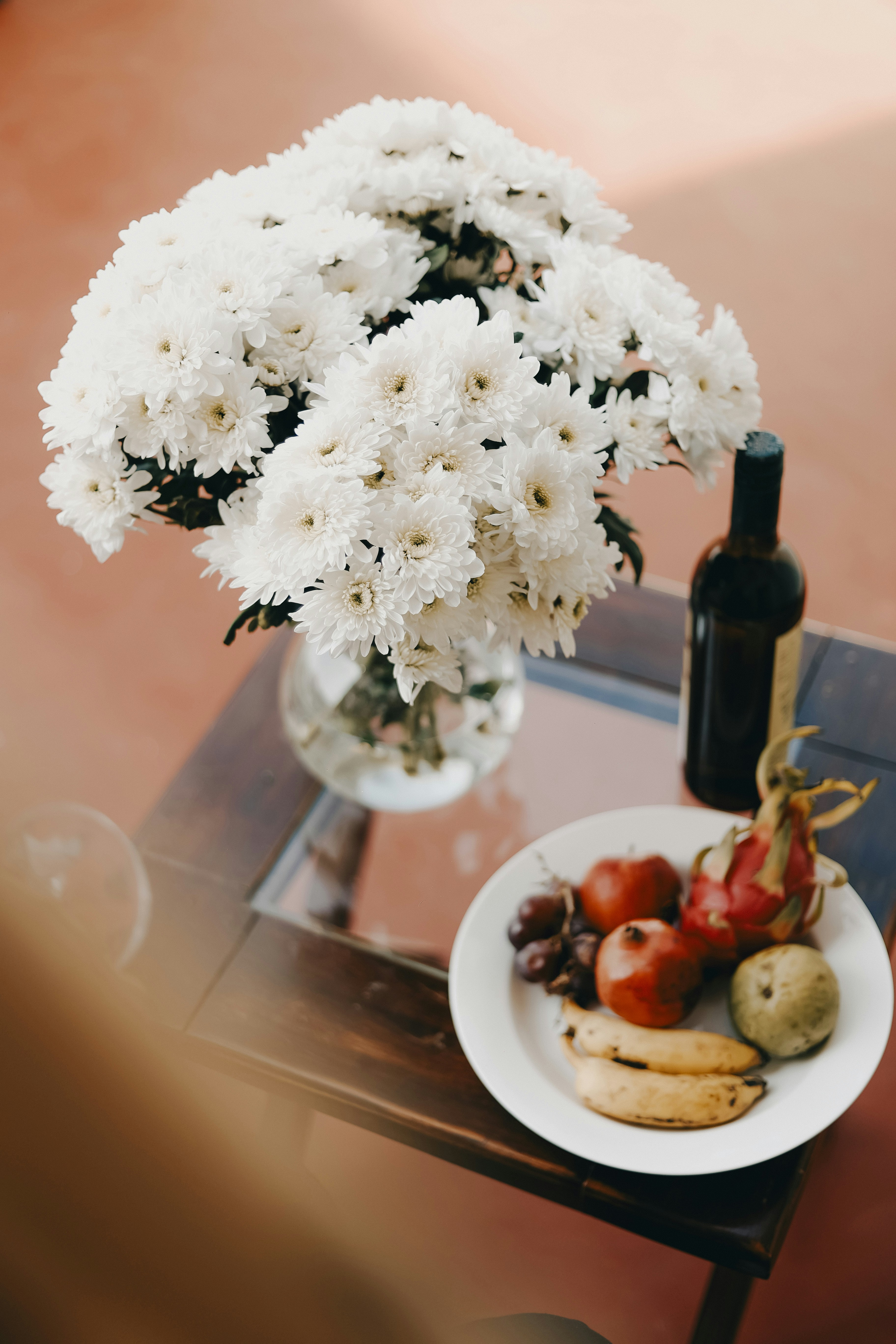 White Chrysanthemum Bouquet Framed by a Still Life of Fruit and Bottle