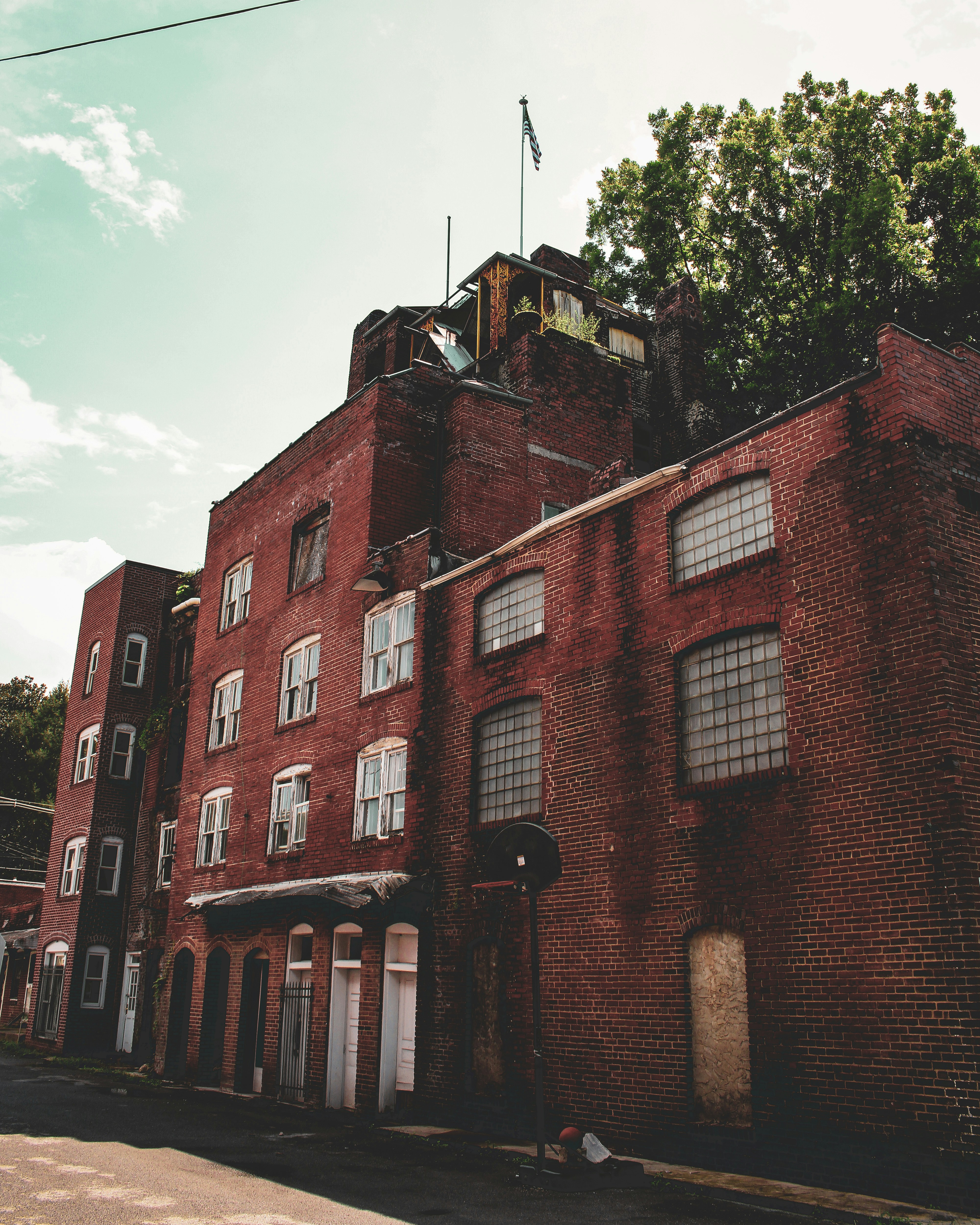 A weathered red brick industrial building with many windows under a cloudy sky