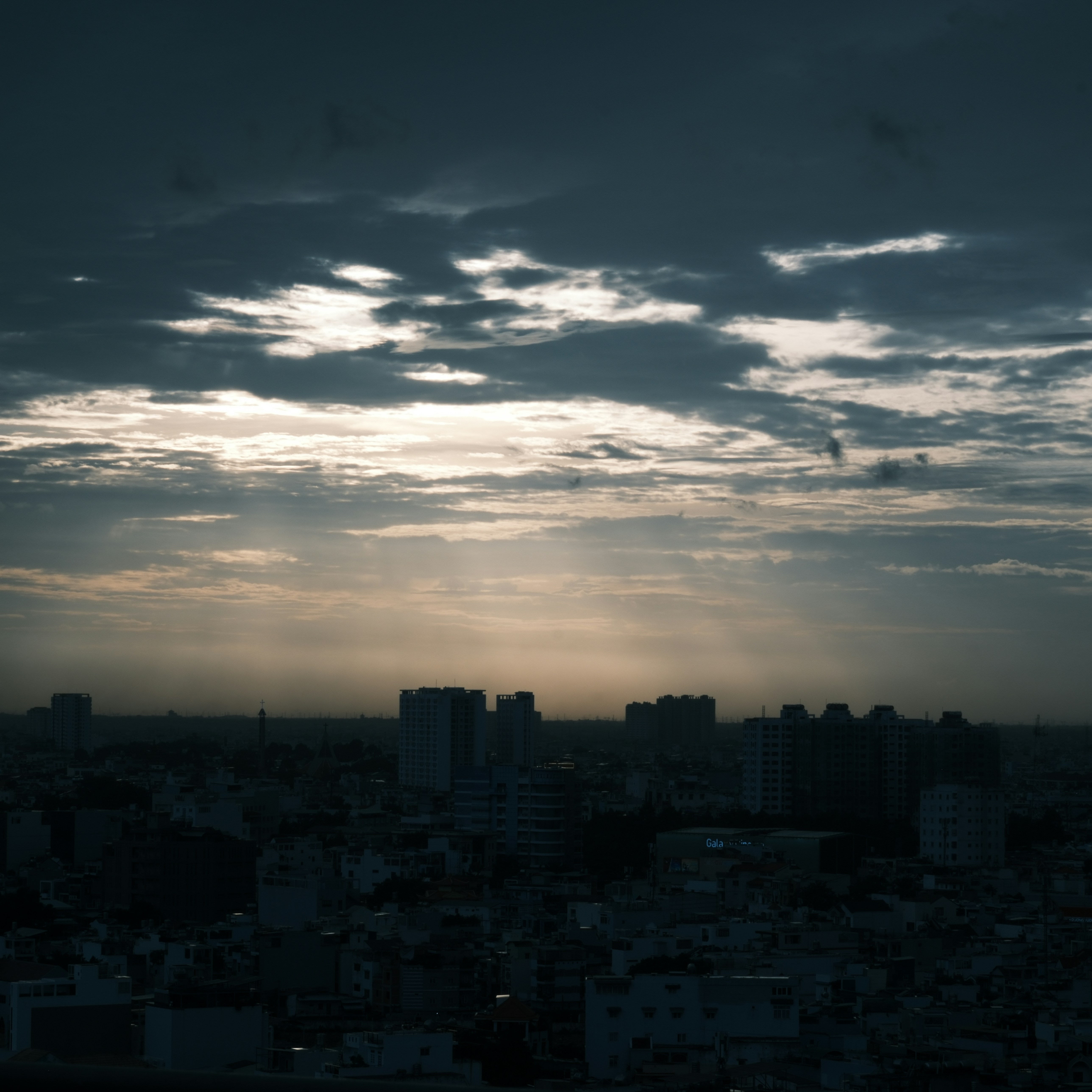 Dawn Over Quiet City: Morning Rays Break Through a Clouded Horizon