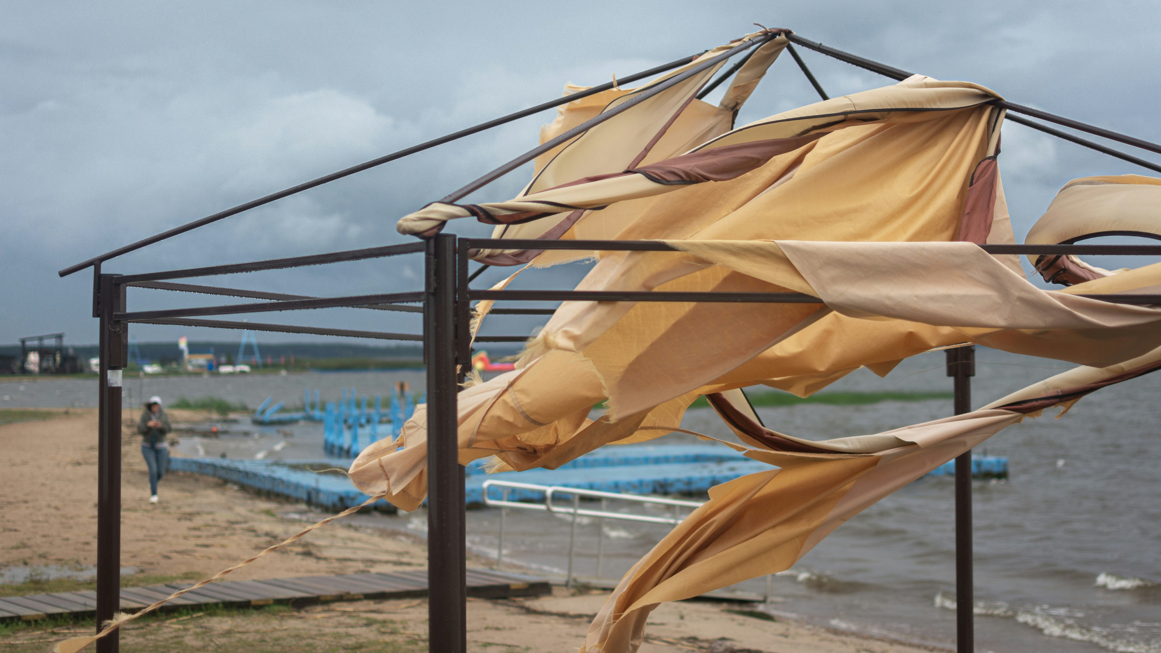 Torn canopies on a windy lakeside promenade