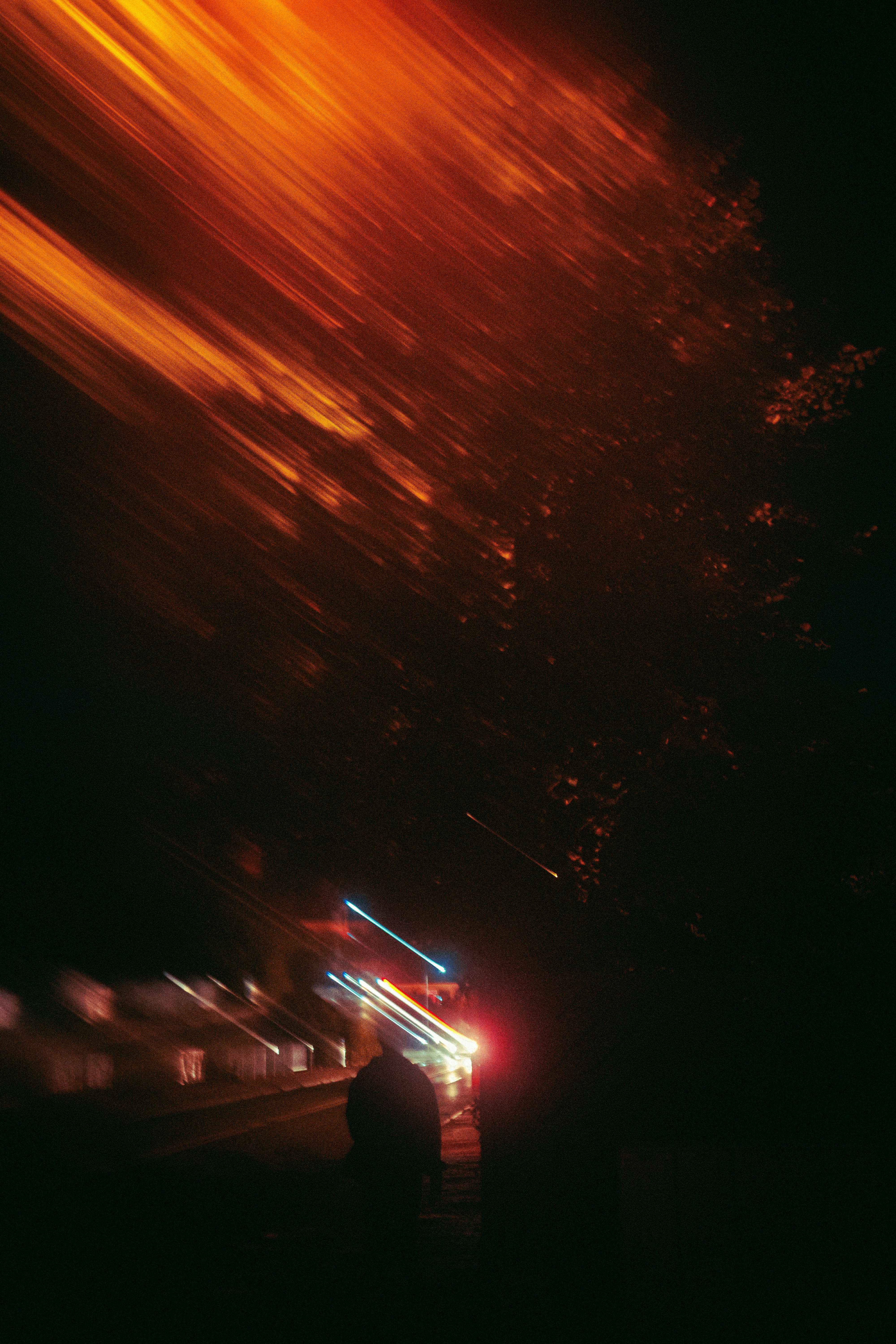 Night Street Blur: a solitary figure beneath moving streetlight trails