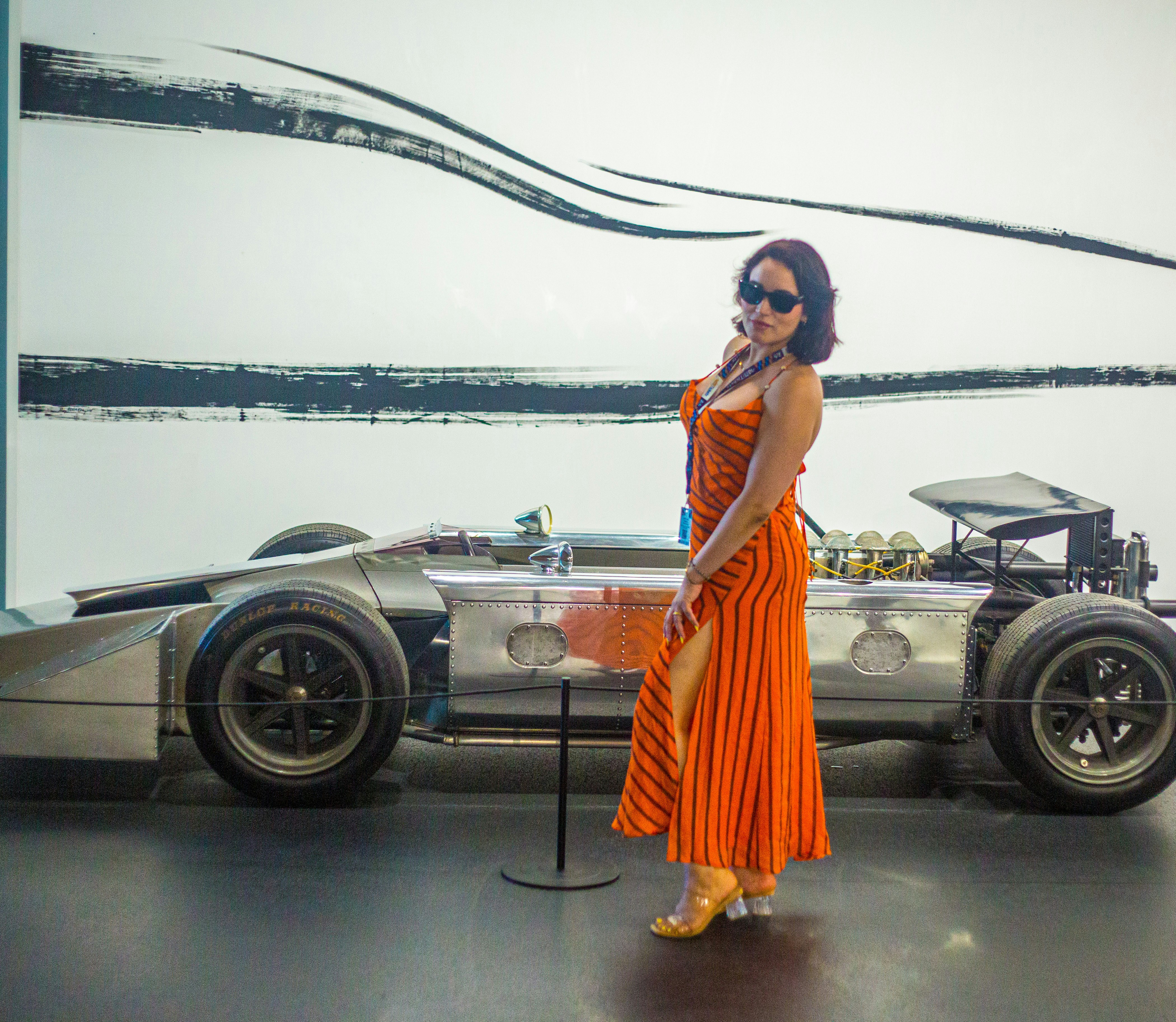 Orange Gown, Chrome Car: A Model Poses by a Vintage Racer