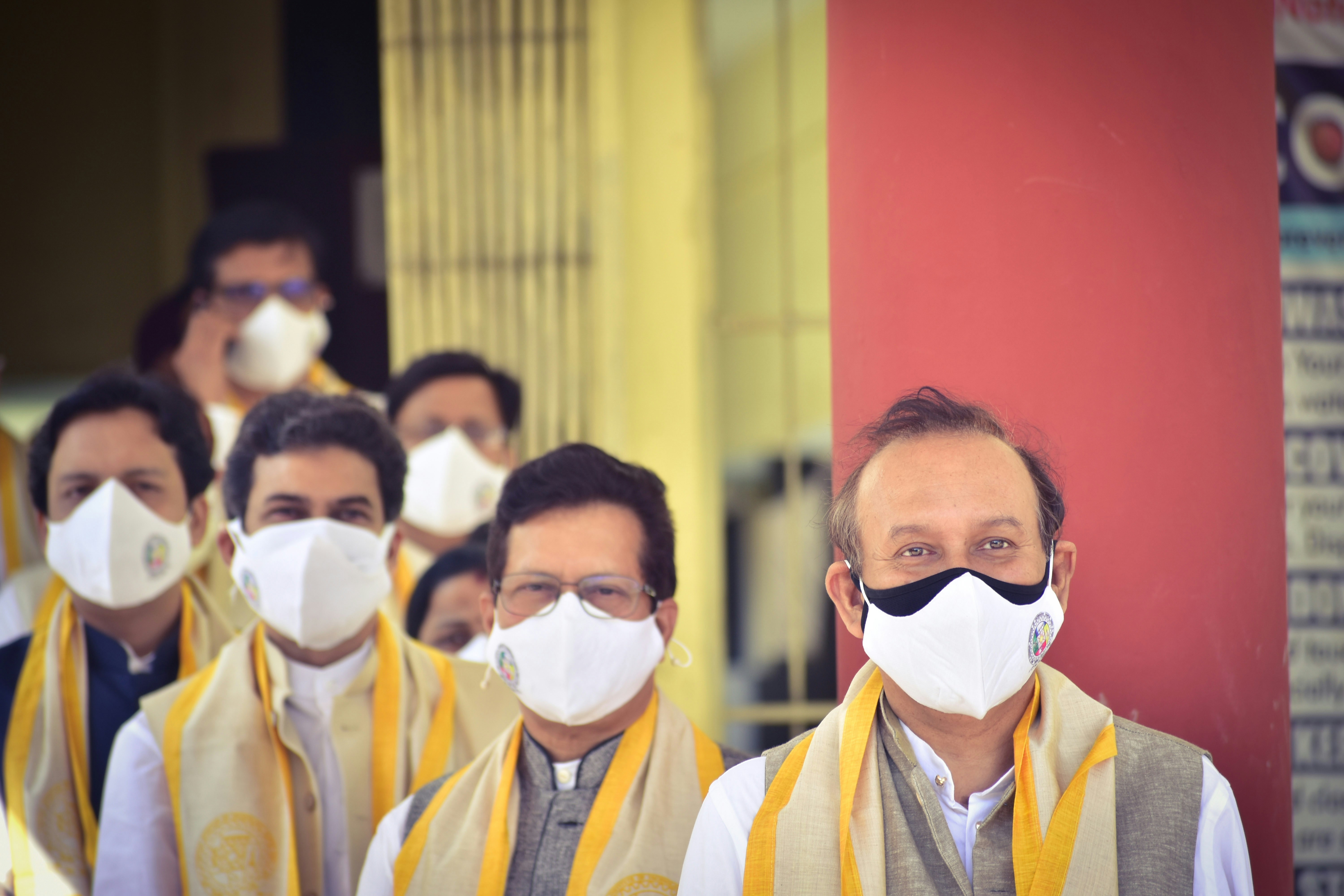 Masked Faces in Line: A Shaded Assembly at the Entrance