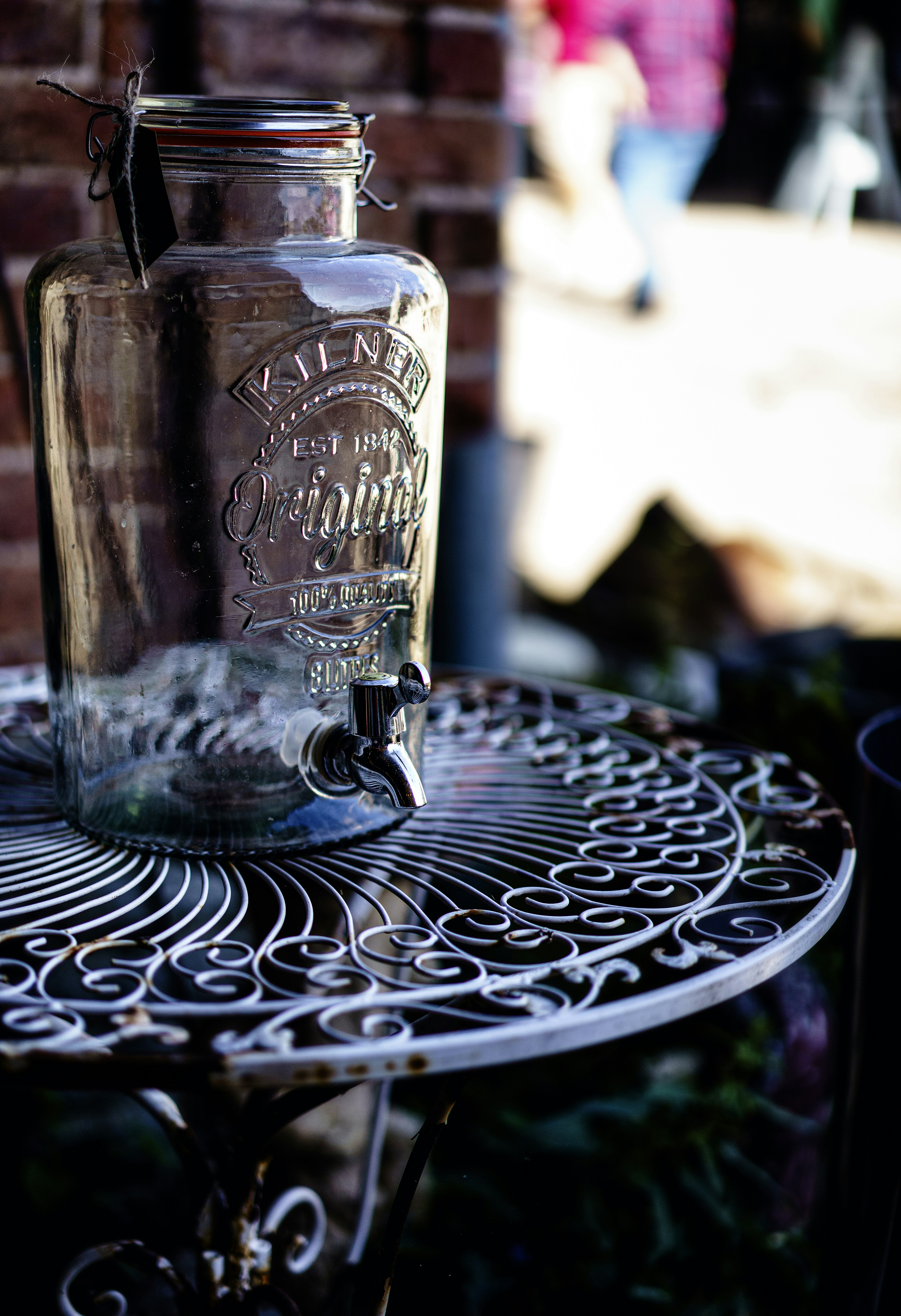 Industrial glass jar on a decorative metal table under bright outdoor light