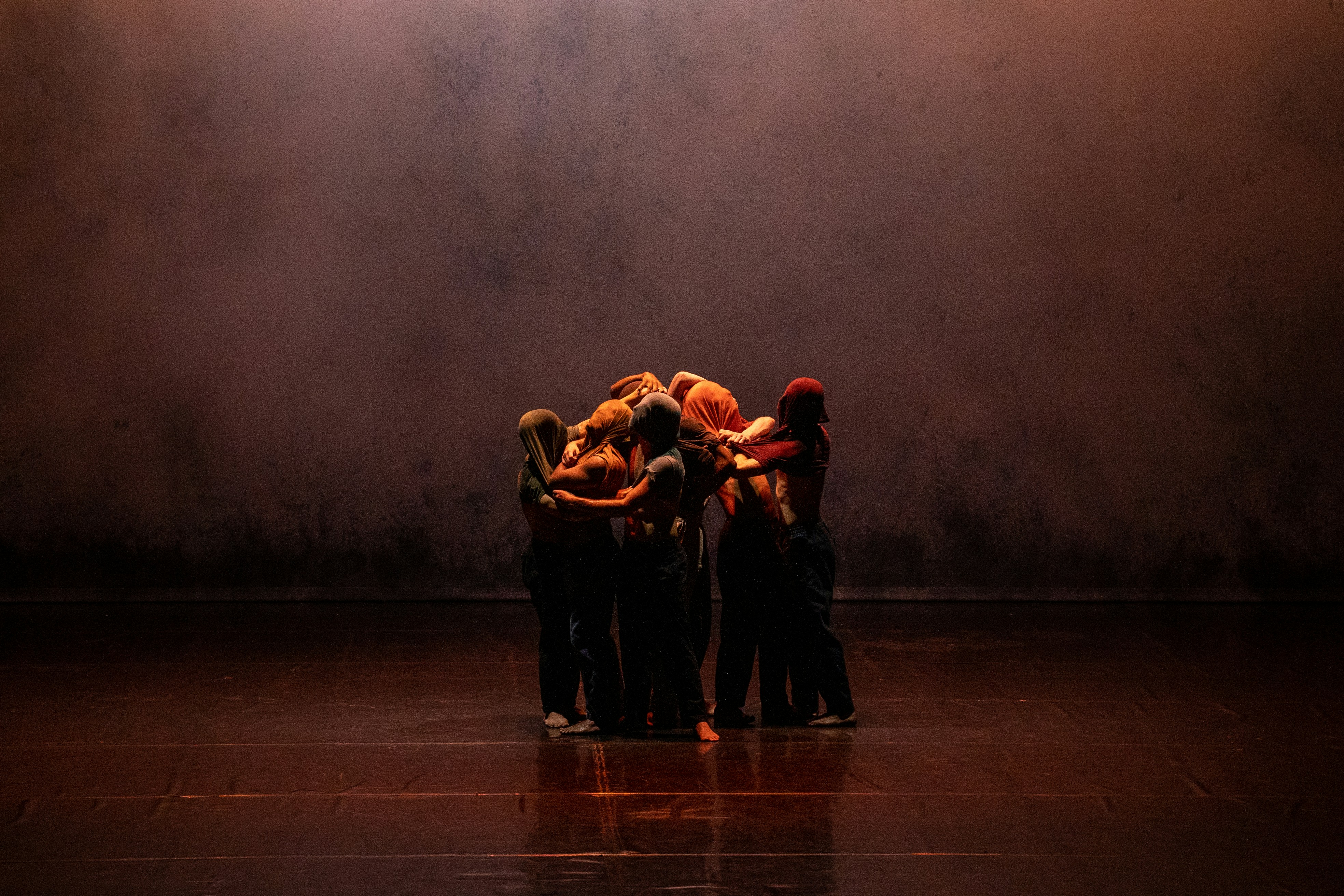 Circle of Voices: Dancers Embrace in Dim Studio
