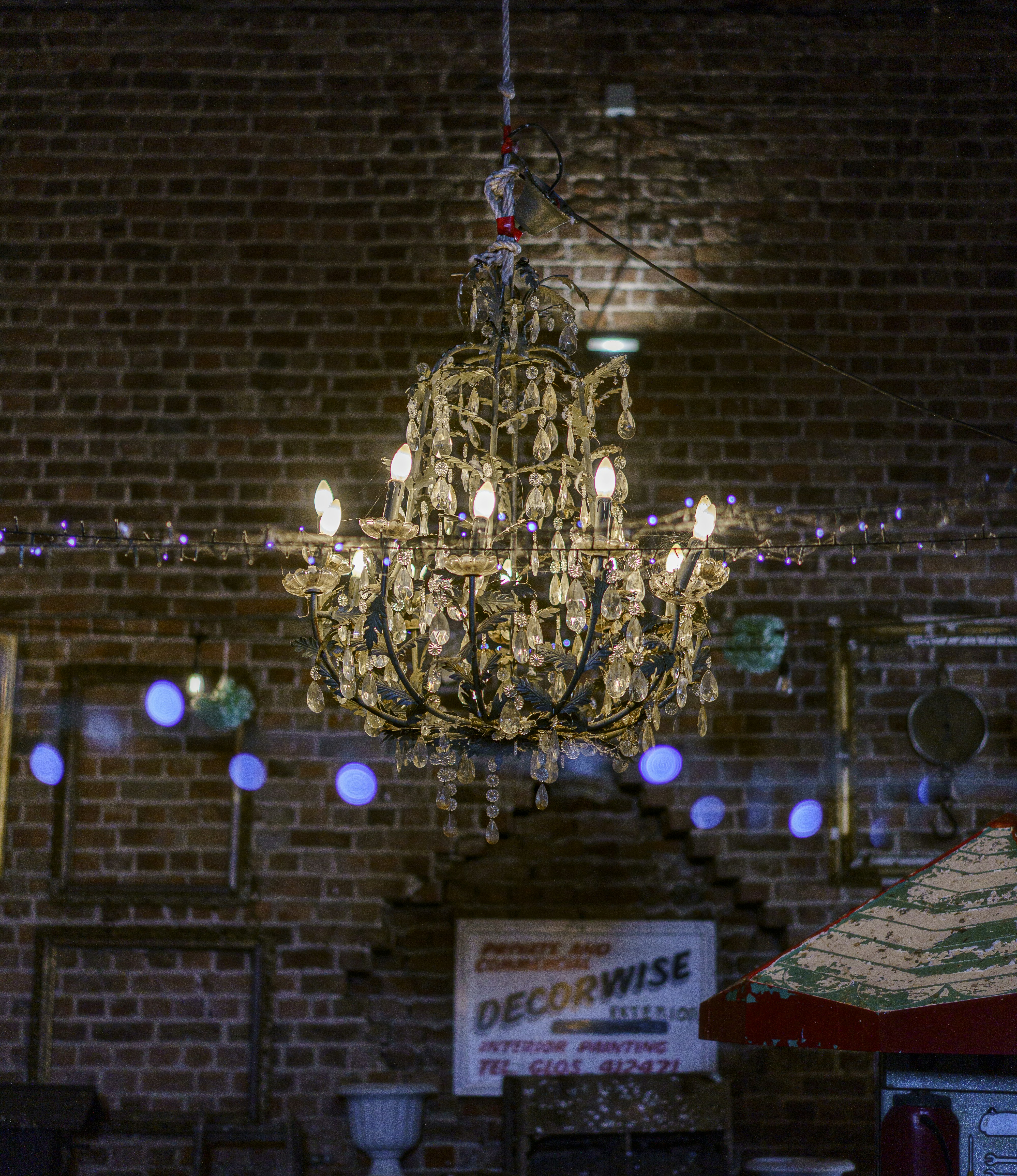 Crystal chandelier glow above rustic brick loft, strings of lights dancing in the background
