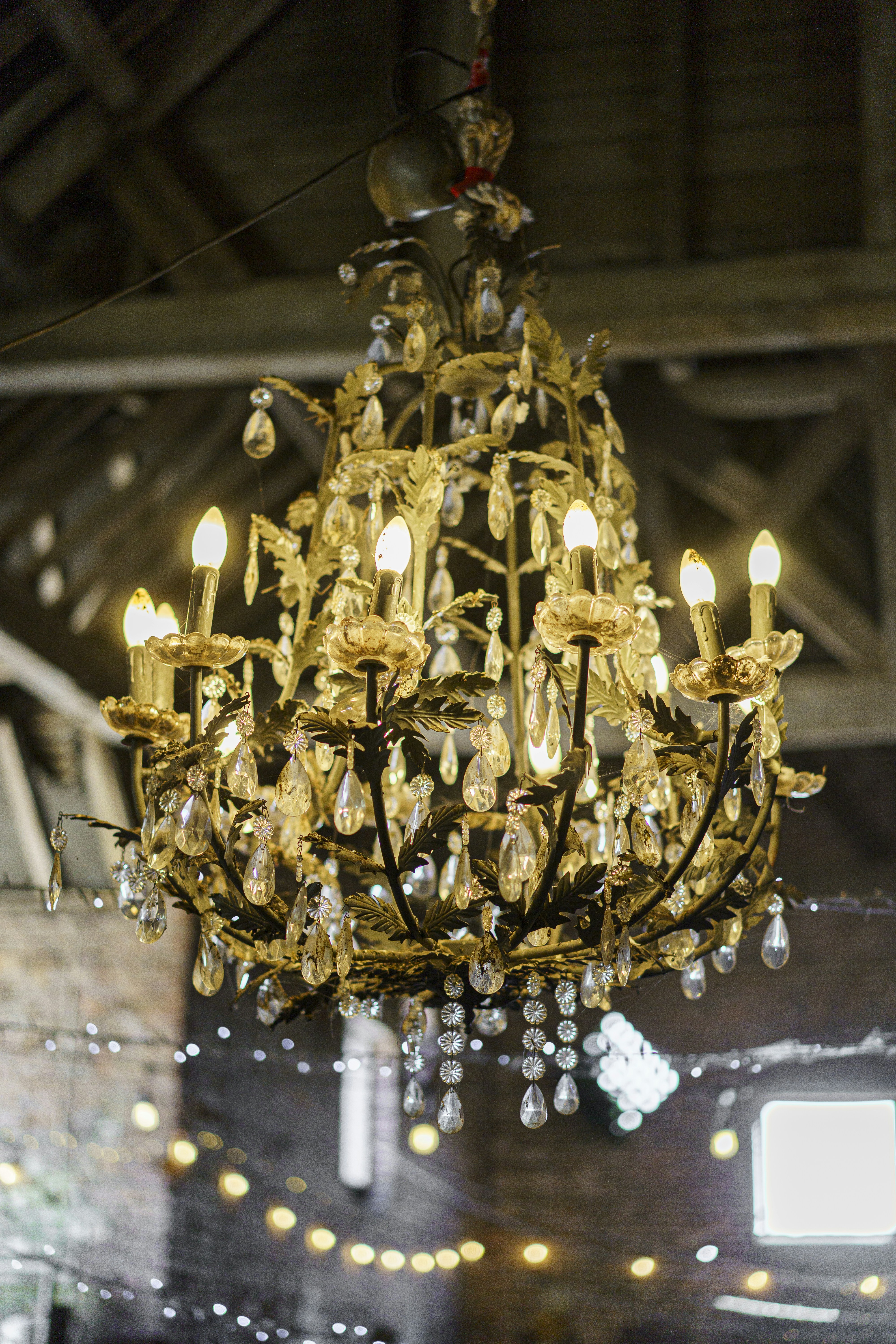 Golden chandelier glow in rustic hall with warm string lights