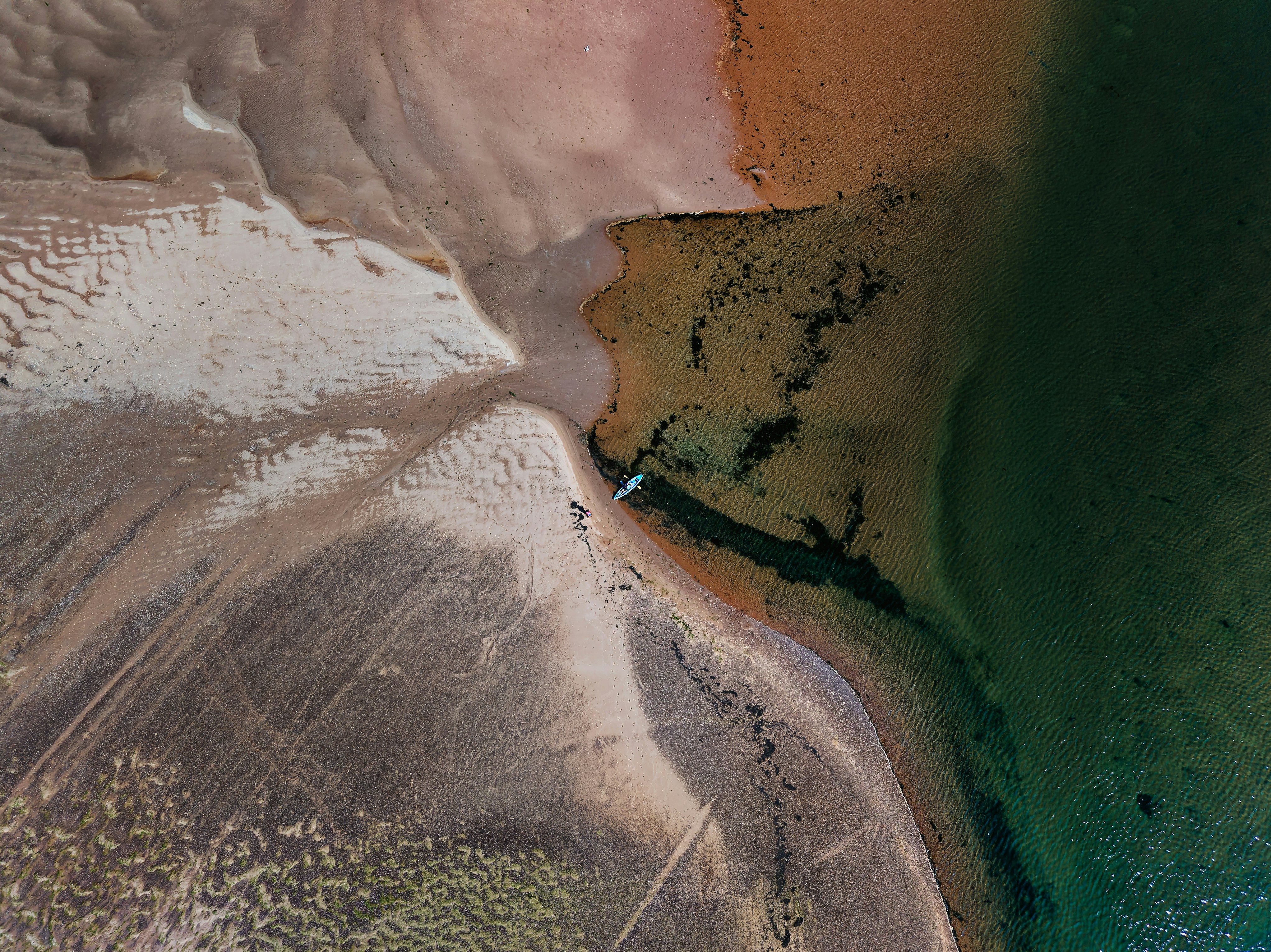 Deserted shoreline carve: tidal patterns meeting emerald water