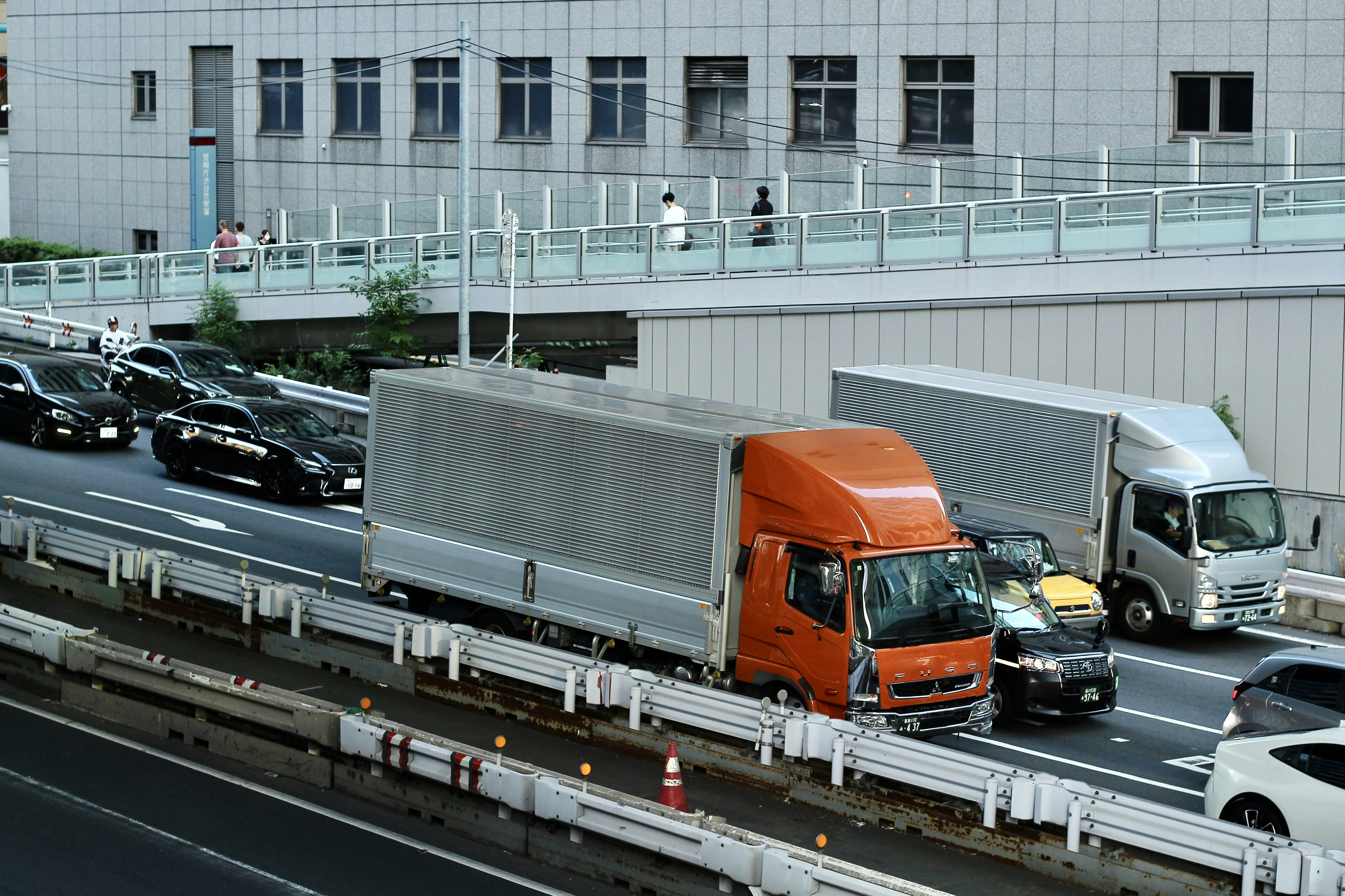 Highway Confluence: Orange Truck Leads a Corridor of Motion