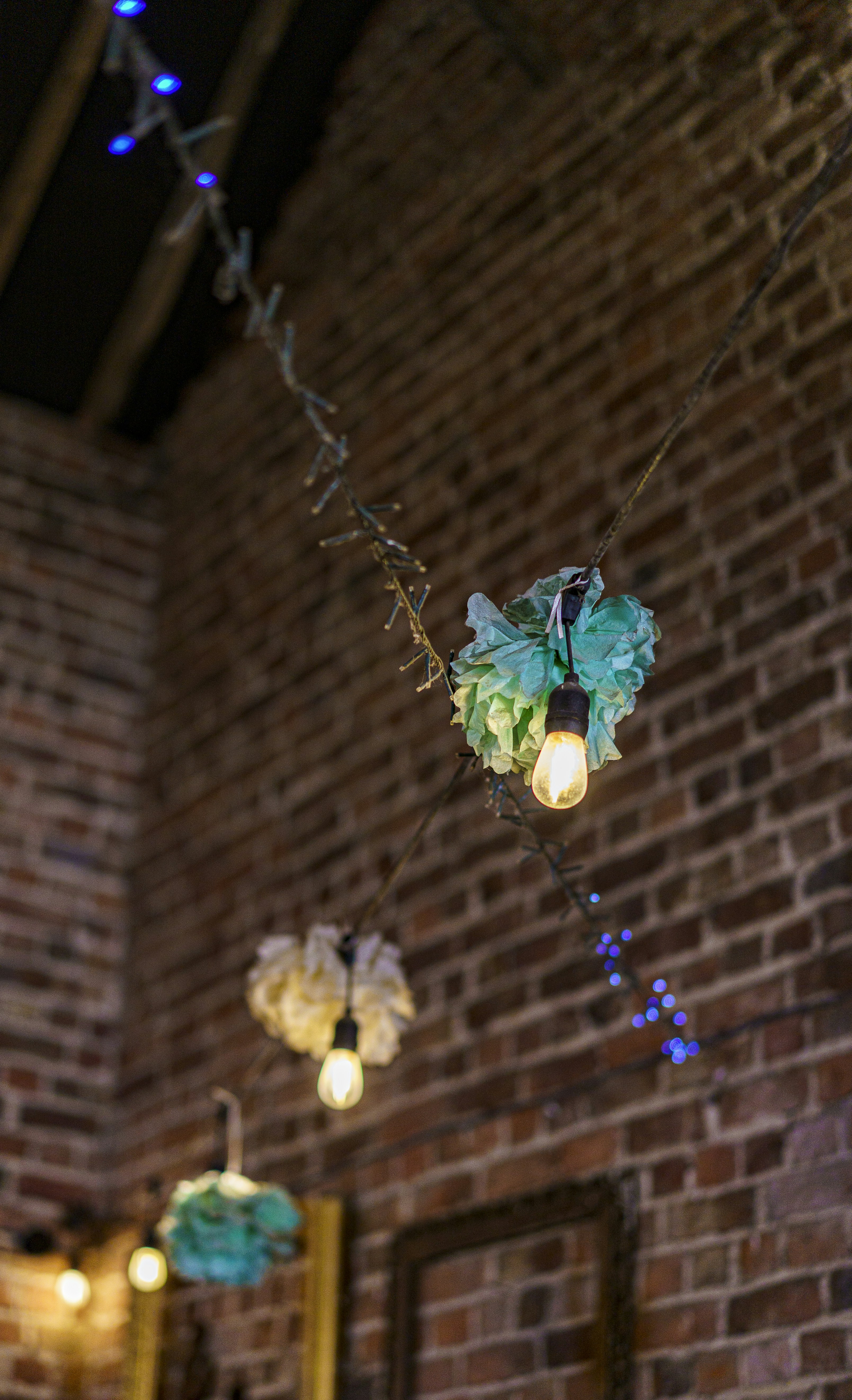 Hanging Glow: Ambient Bulbs and Tissue Lanterns Against Brickback Wall