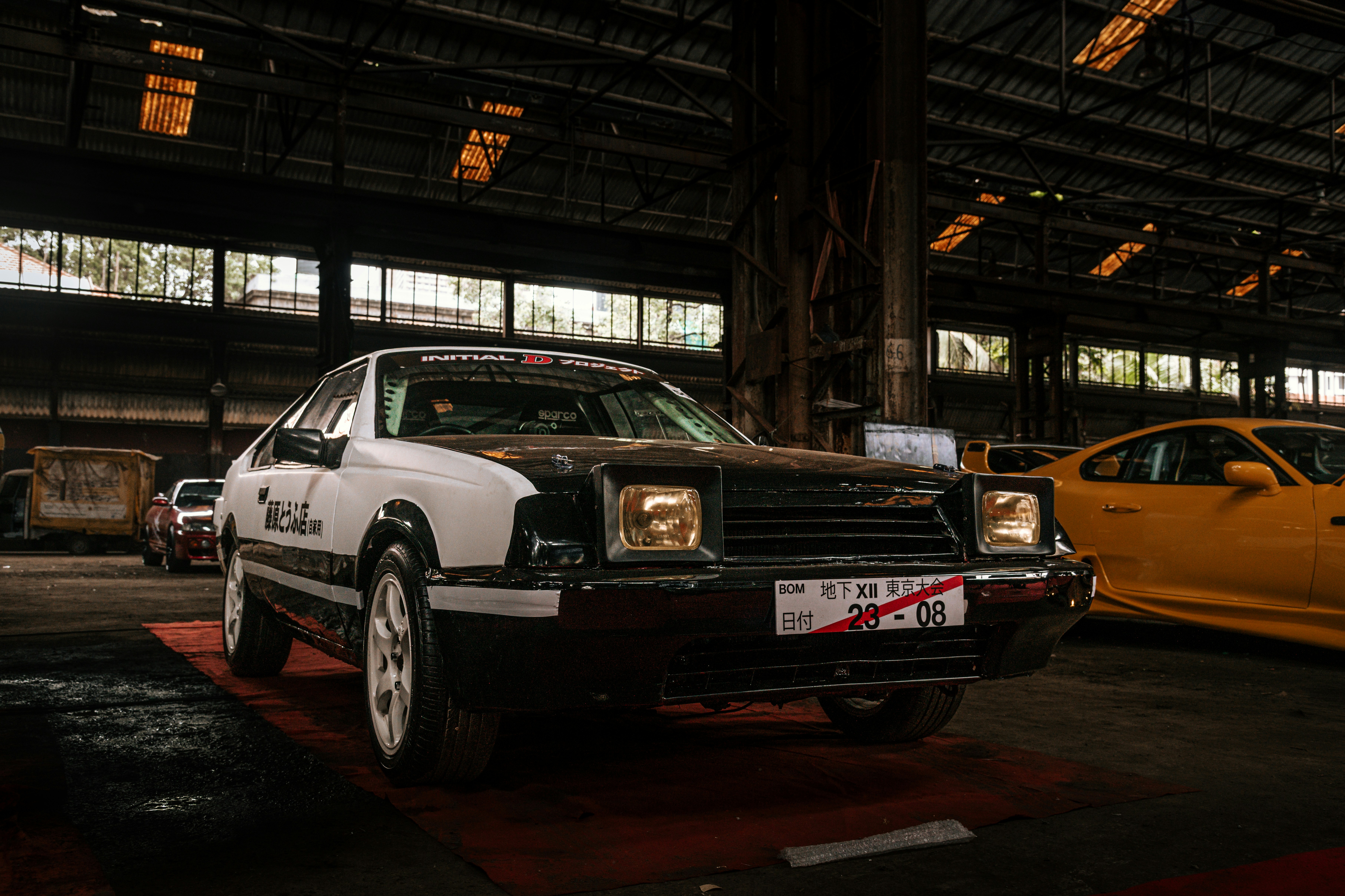 Restored white rally coupe under factory dim lights