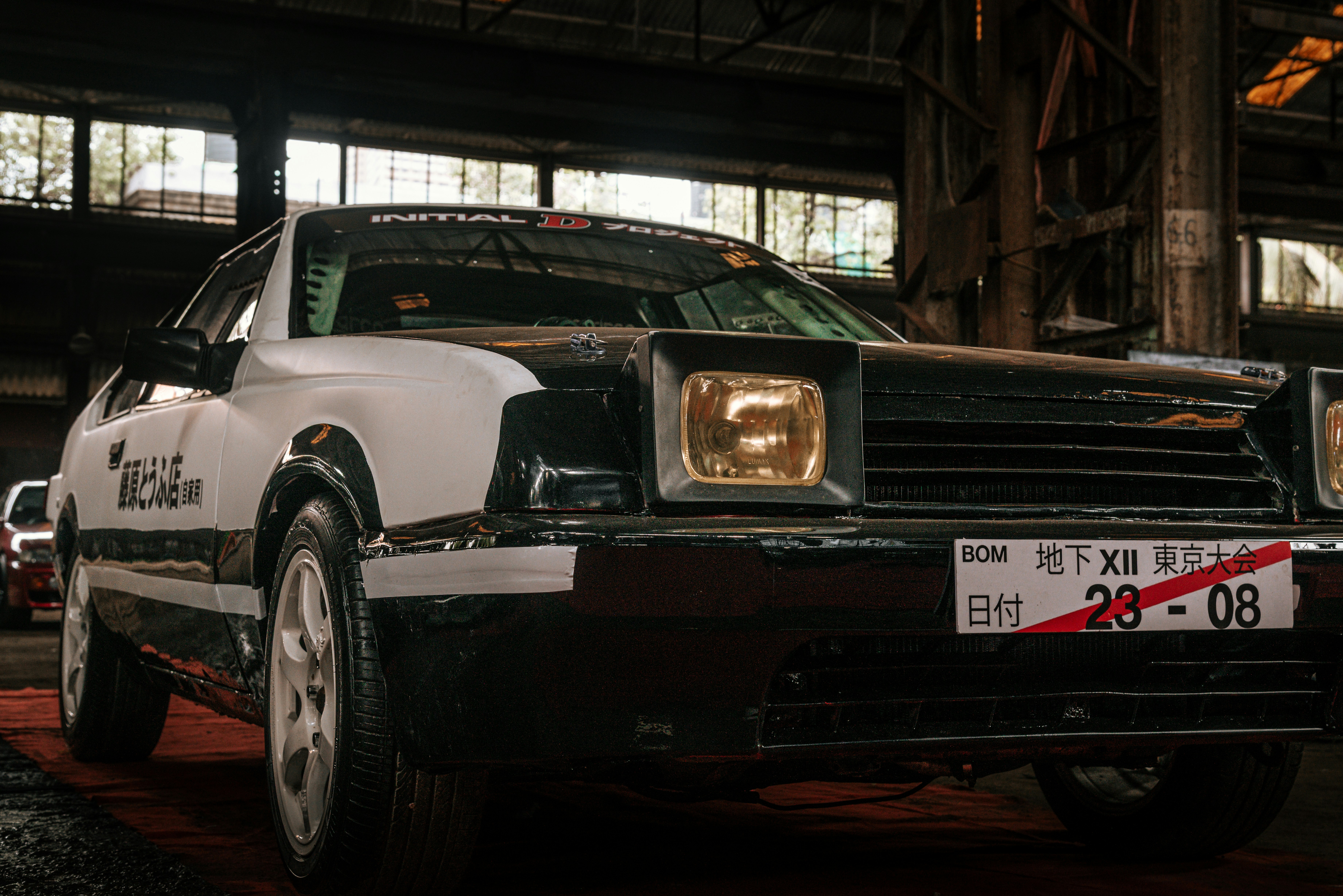 A Classic Car Resting Under Industrial Shadows