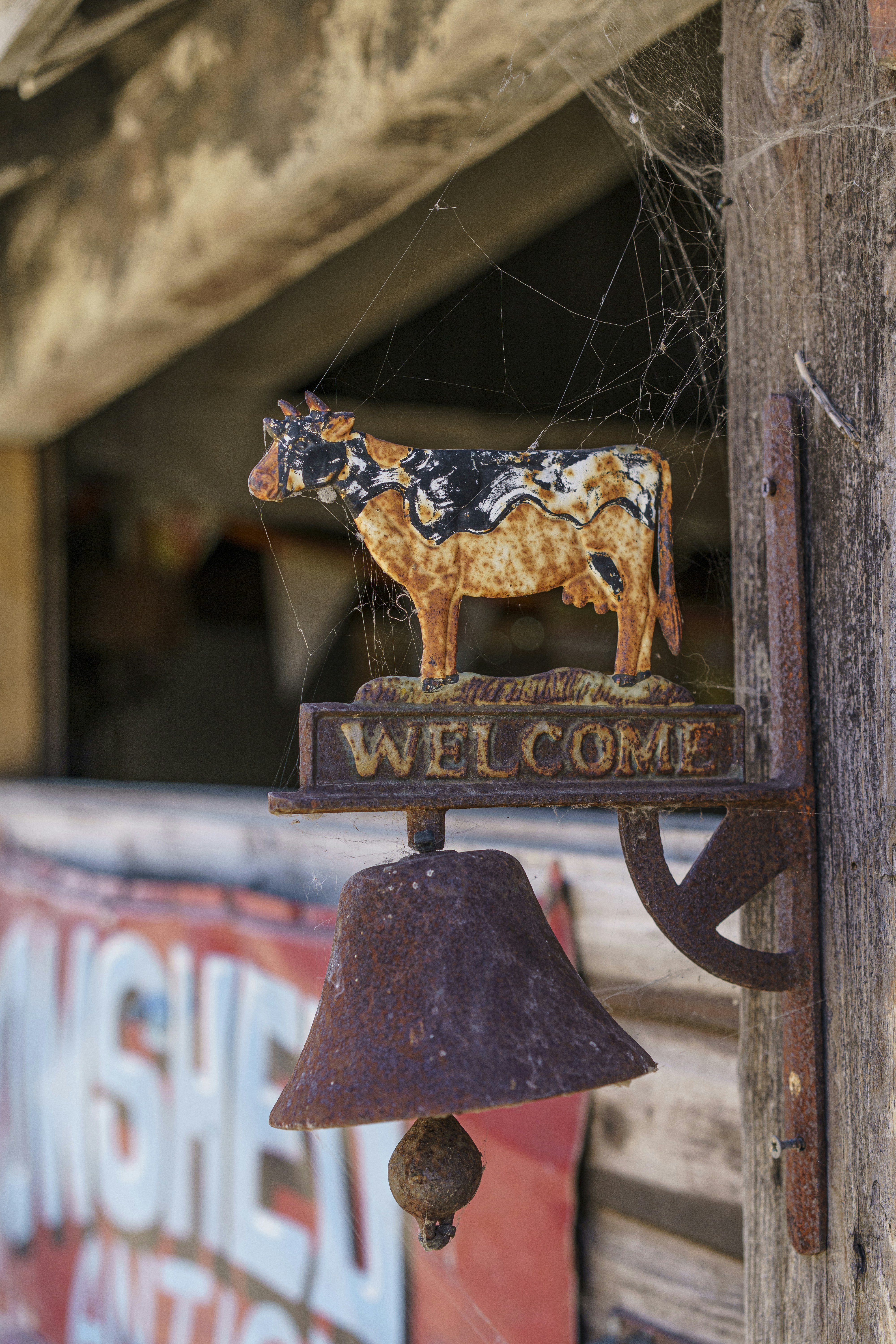 Rust and Welcome: A Weathered Bell Statue Adorns a Crumbling Exterior