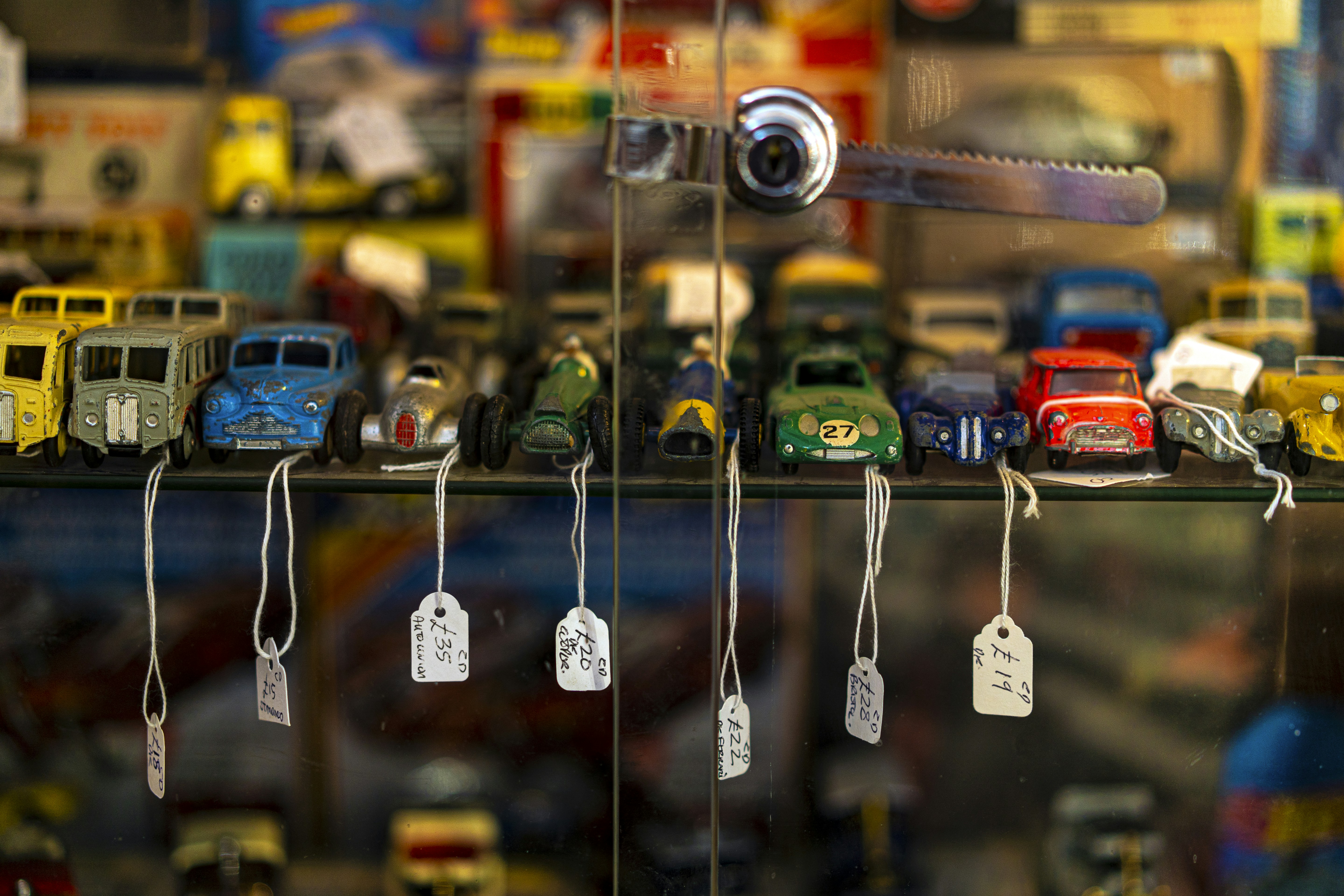 Vintage toy cars with price tags on a glass shelf in a shop
