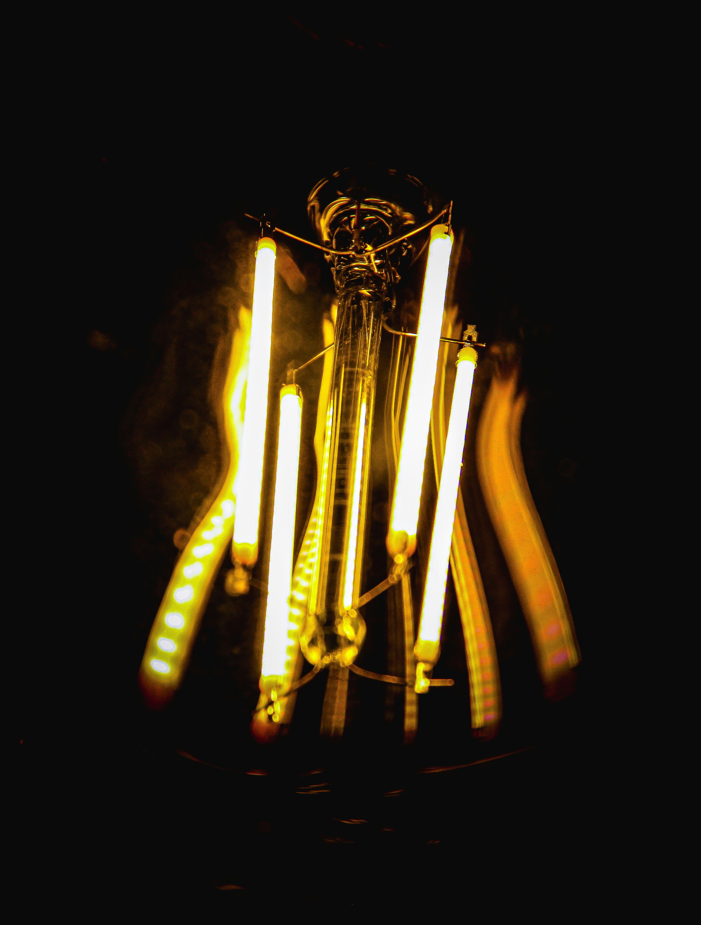 A close-up of glowing tungsten filaments in a vintage Edison bulb set against black, highlighting warm amber tones and intricate glass structure.