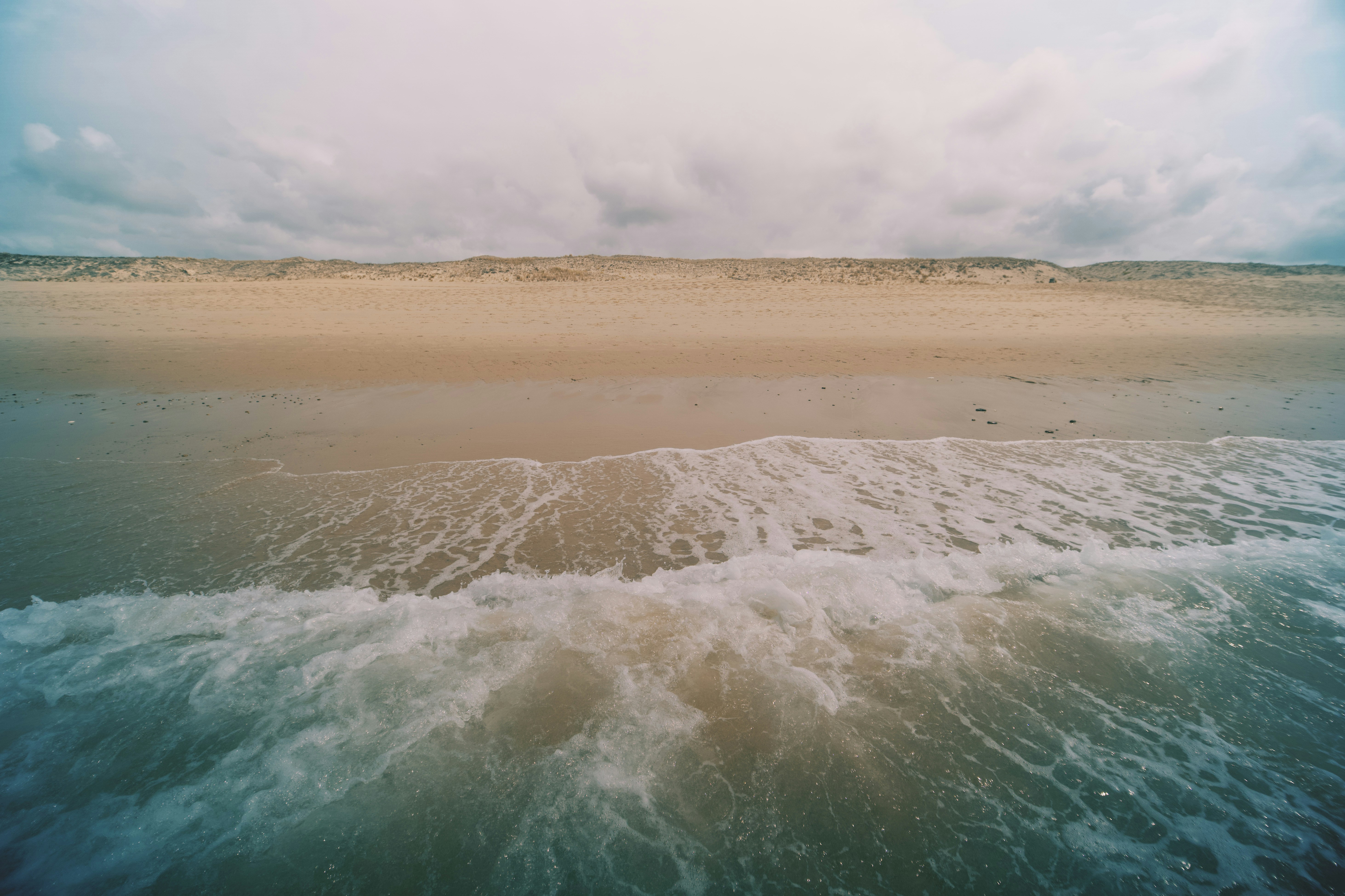 Horizon of Quiet Tide: Beach and Ocean Meeting the Distant Dunes