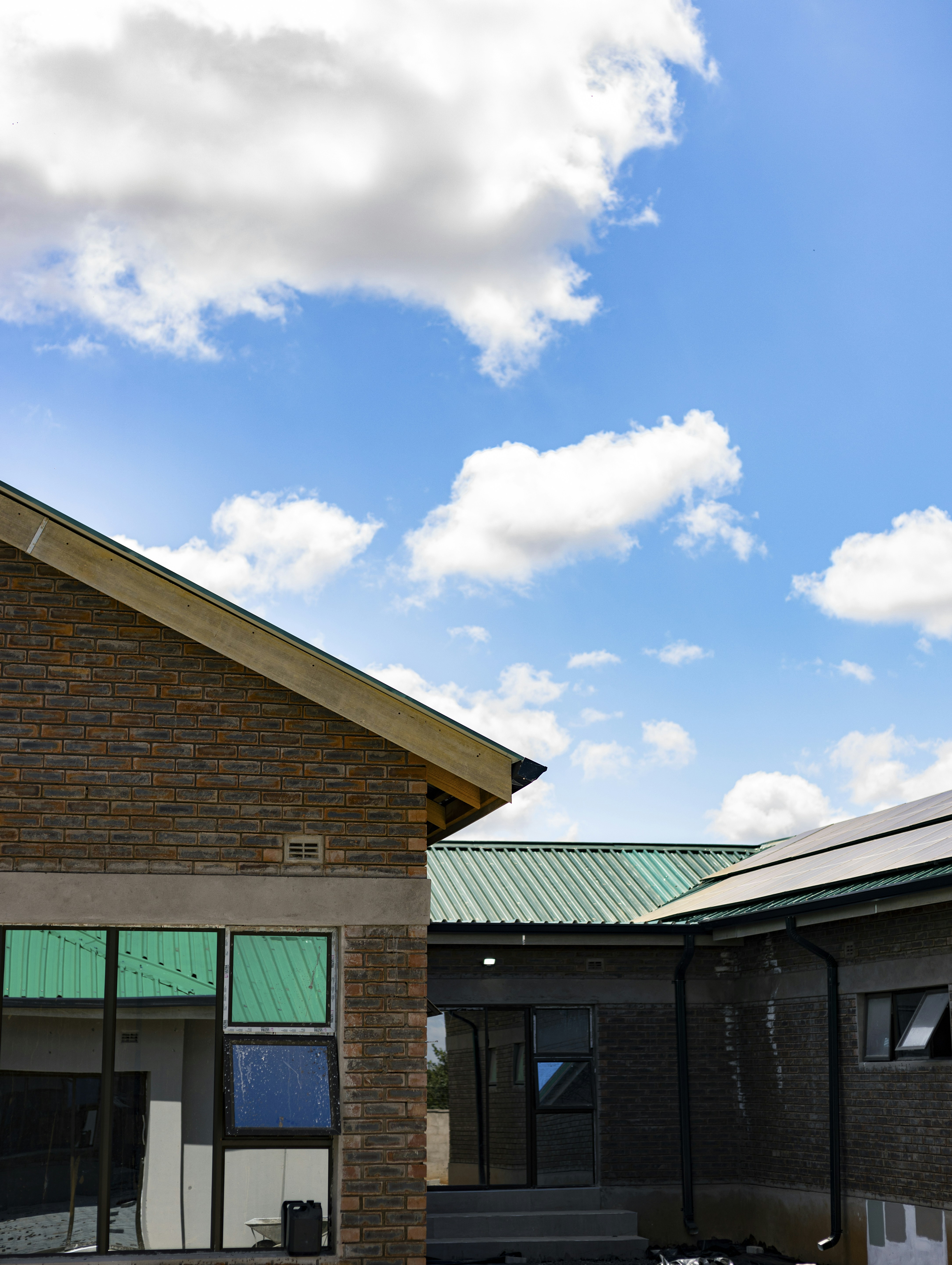 Brick Facade Under a Bright Sky with Green Roof Trim