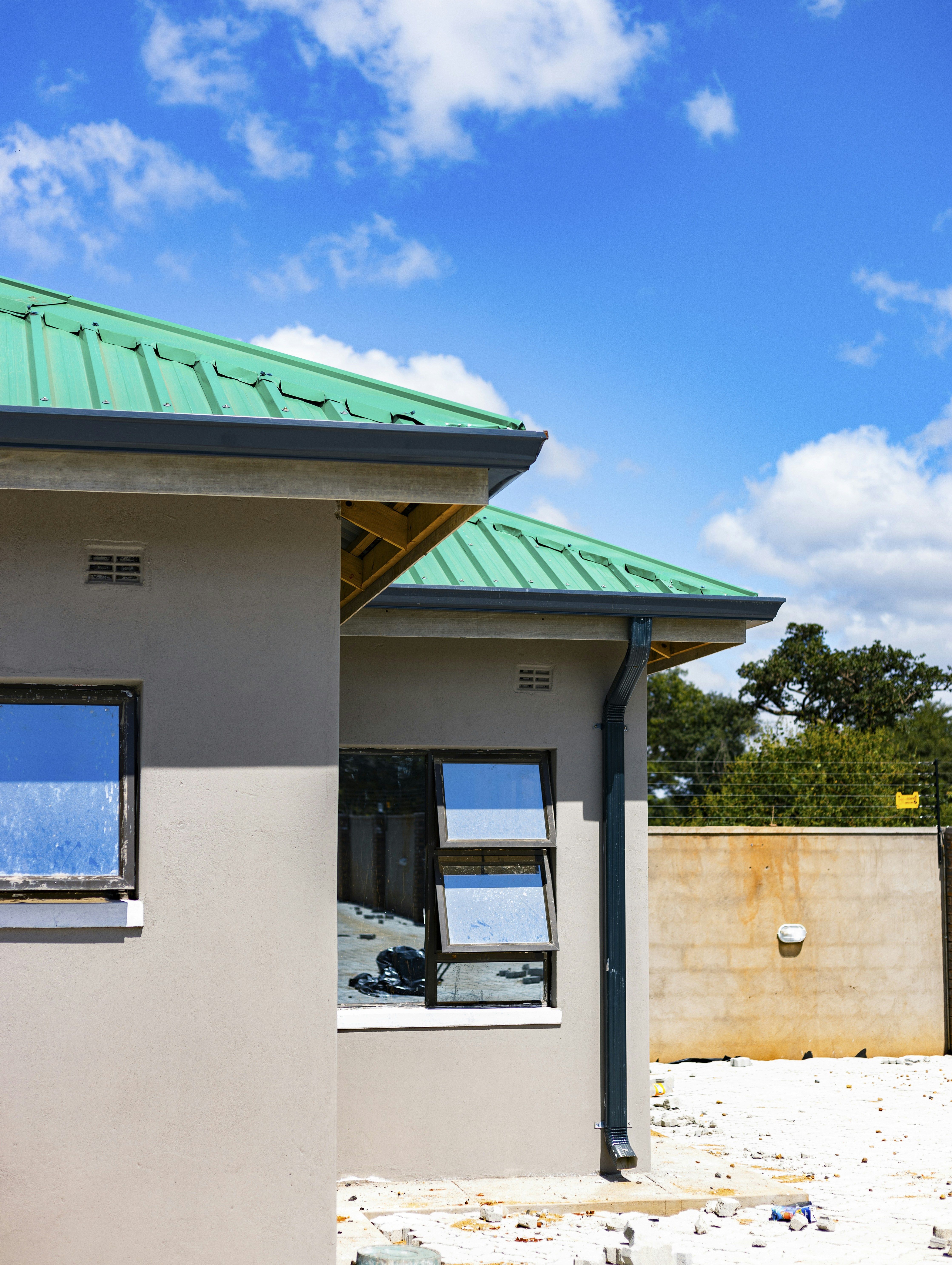 Construction Corner: Sunlit Wall and Green Roof Under a Bright Sky
