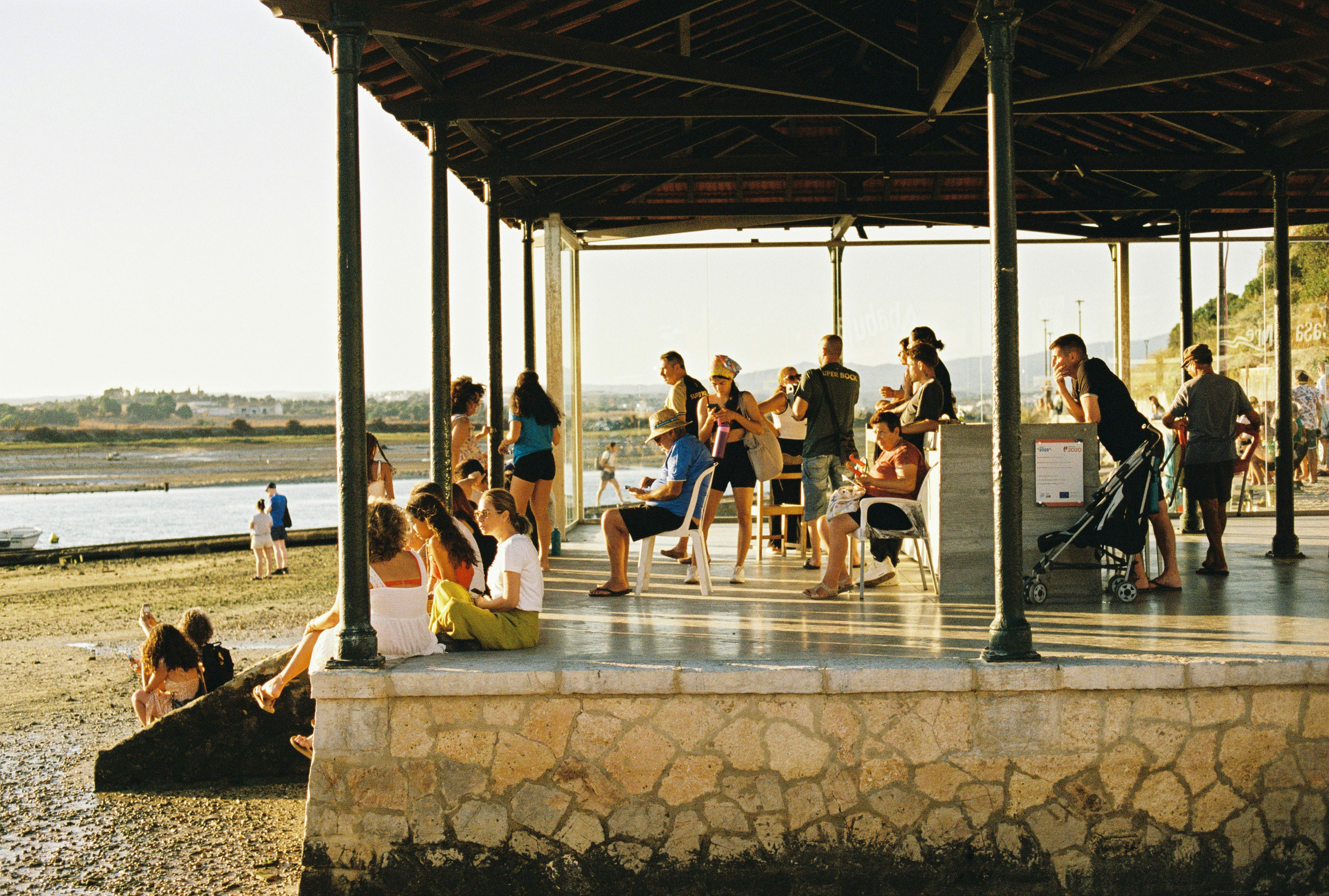 Sunlit Pavilion of People: A Quiet Assembly by the Shore