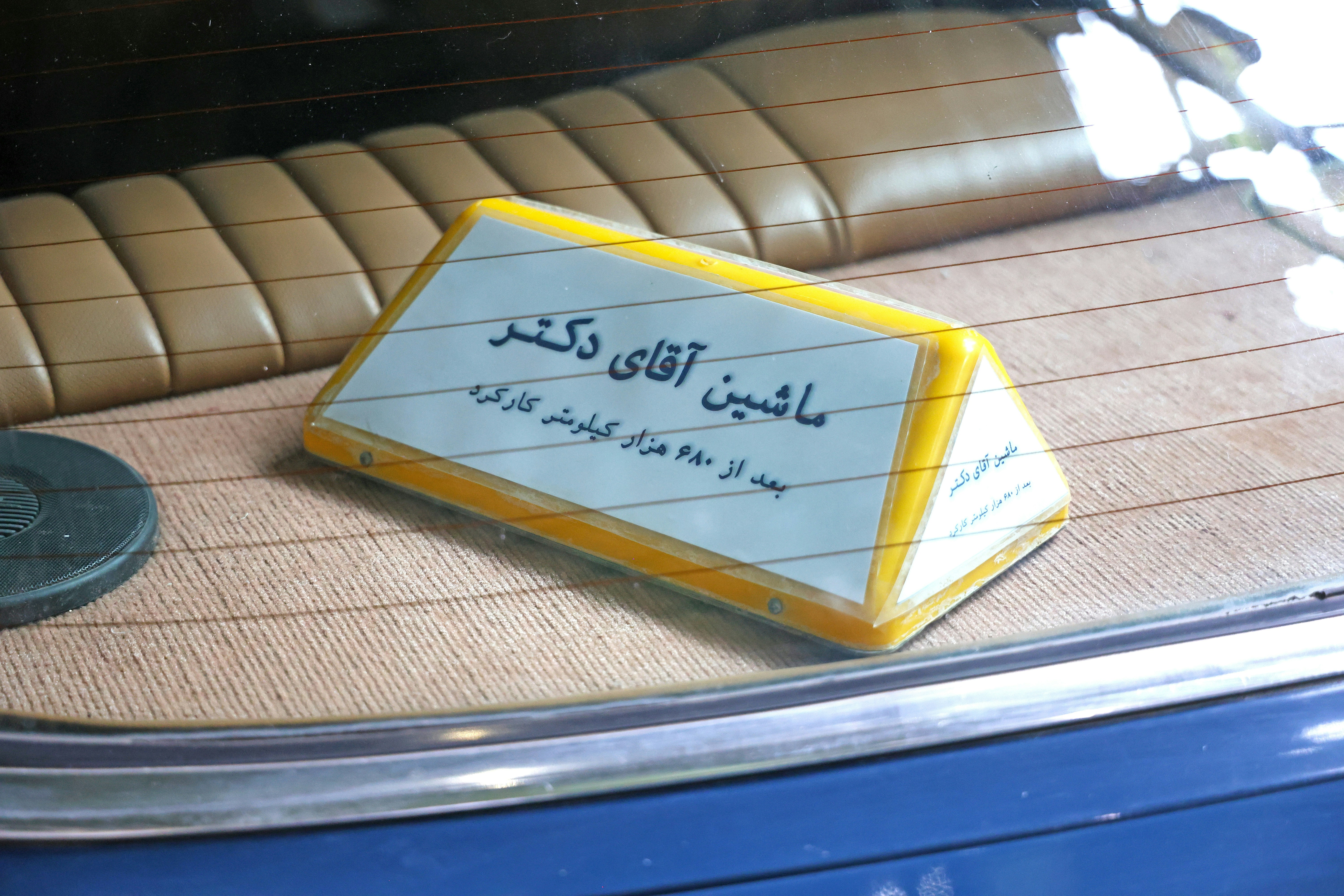 Yellow-Trimmed Sign Resting on Car Carpet Inside a Classic Vehicle