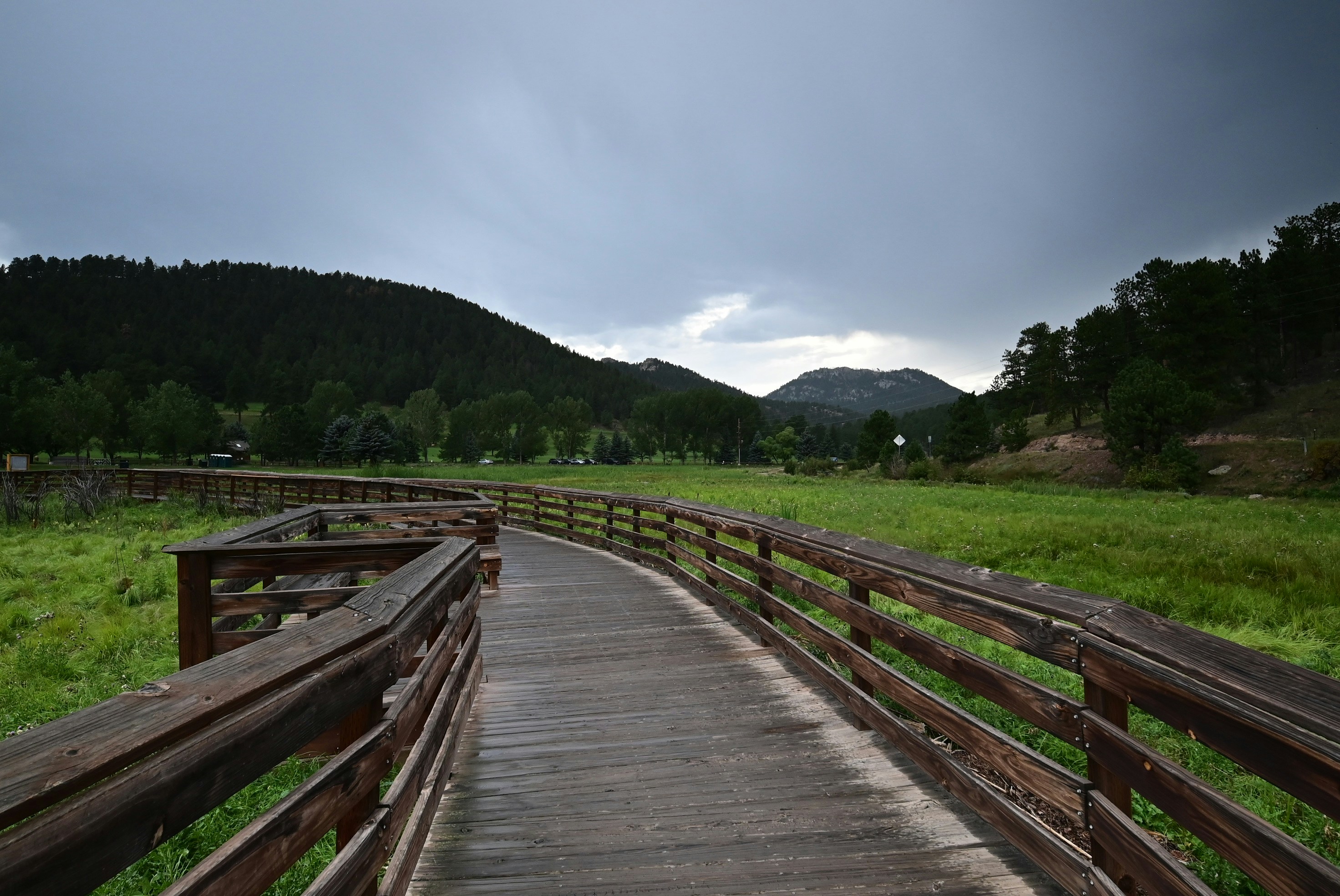 Wooden Bridge Reaches Toward rolling hills Under a Stormy Sky