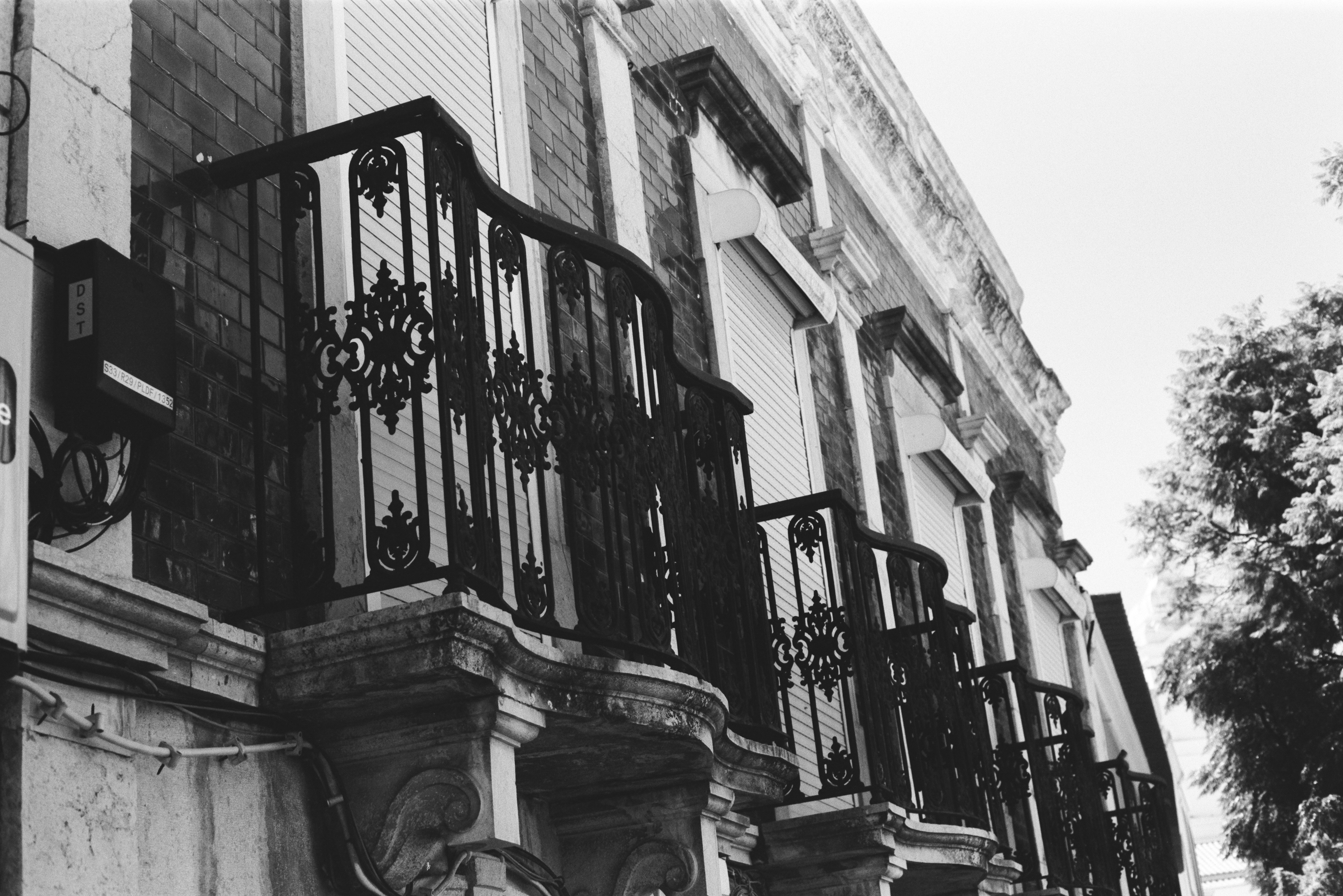 Black-and-white street scene highlighting ornate iron balcony railings along a row of buildings.