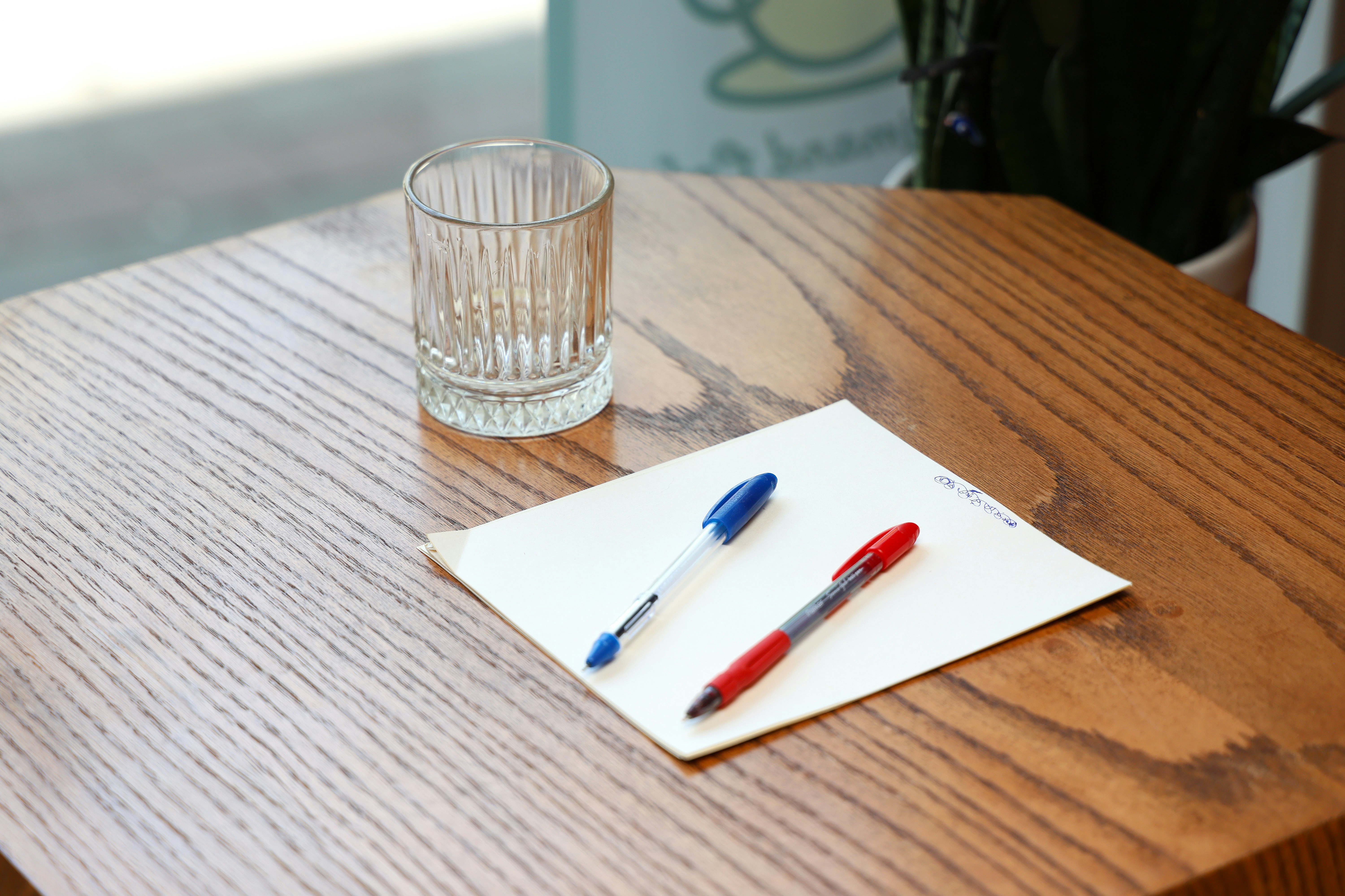 Two Gel Pens on a White Note Resting on a Wooden Table