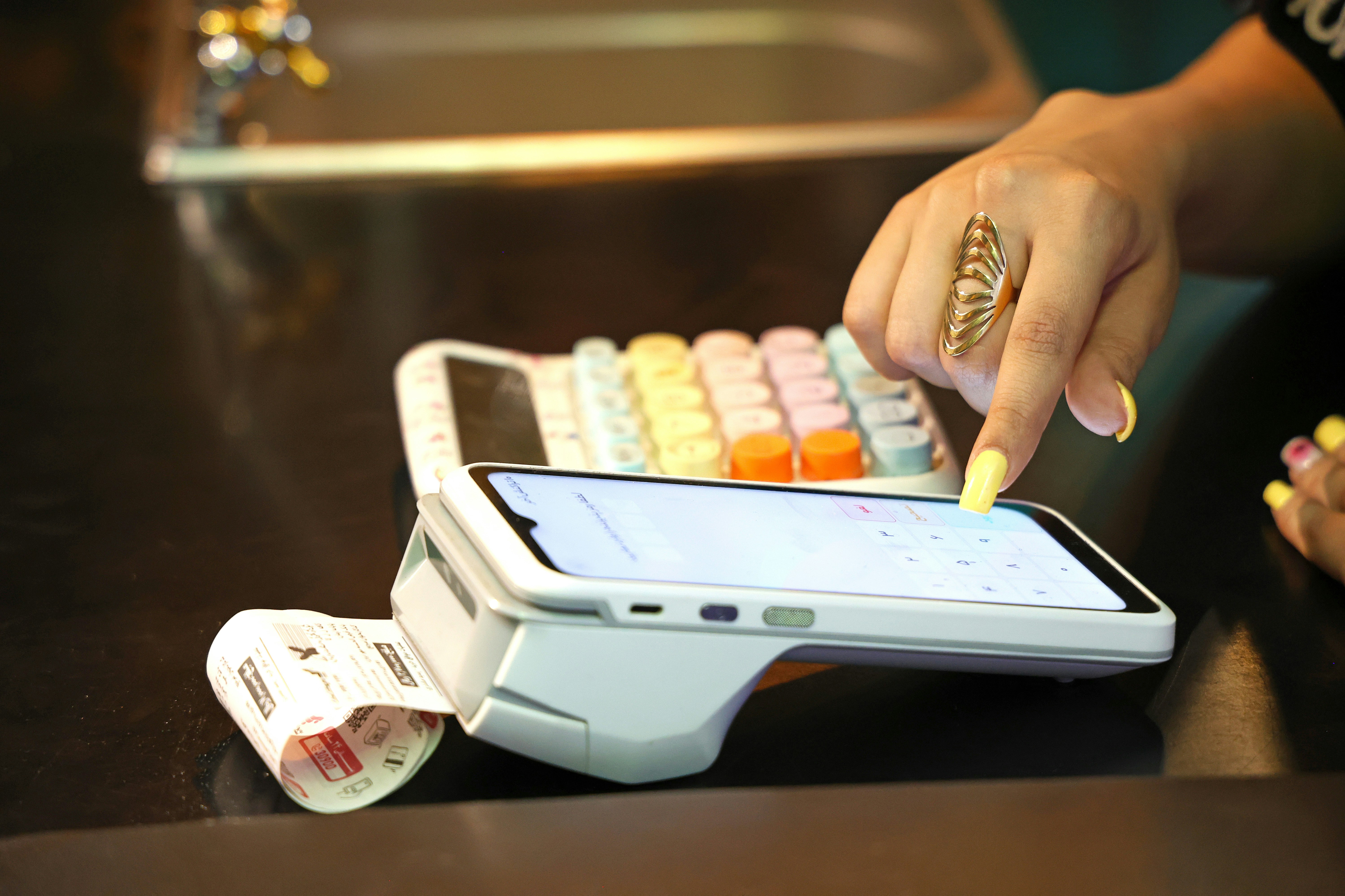 Touchscreen Checkout: Fingers, Card Reader, and Colorful Keypad at a Counter