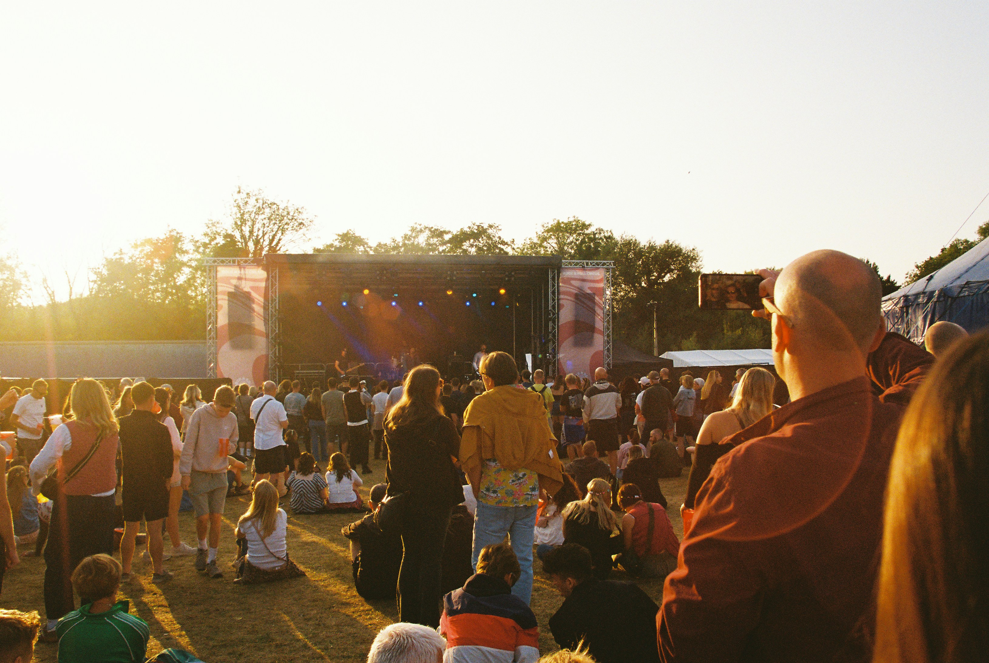 Sunlit Stage Watch: Festival Scene Framed by Attentive Crowd