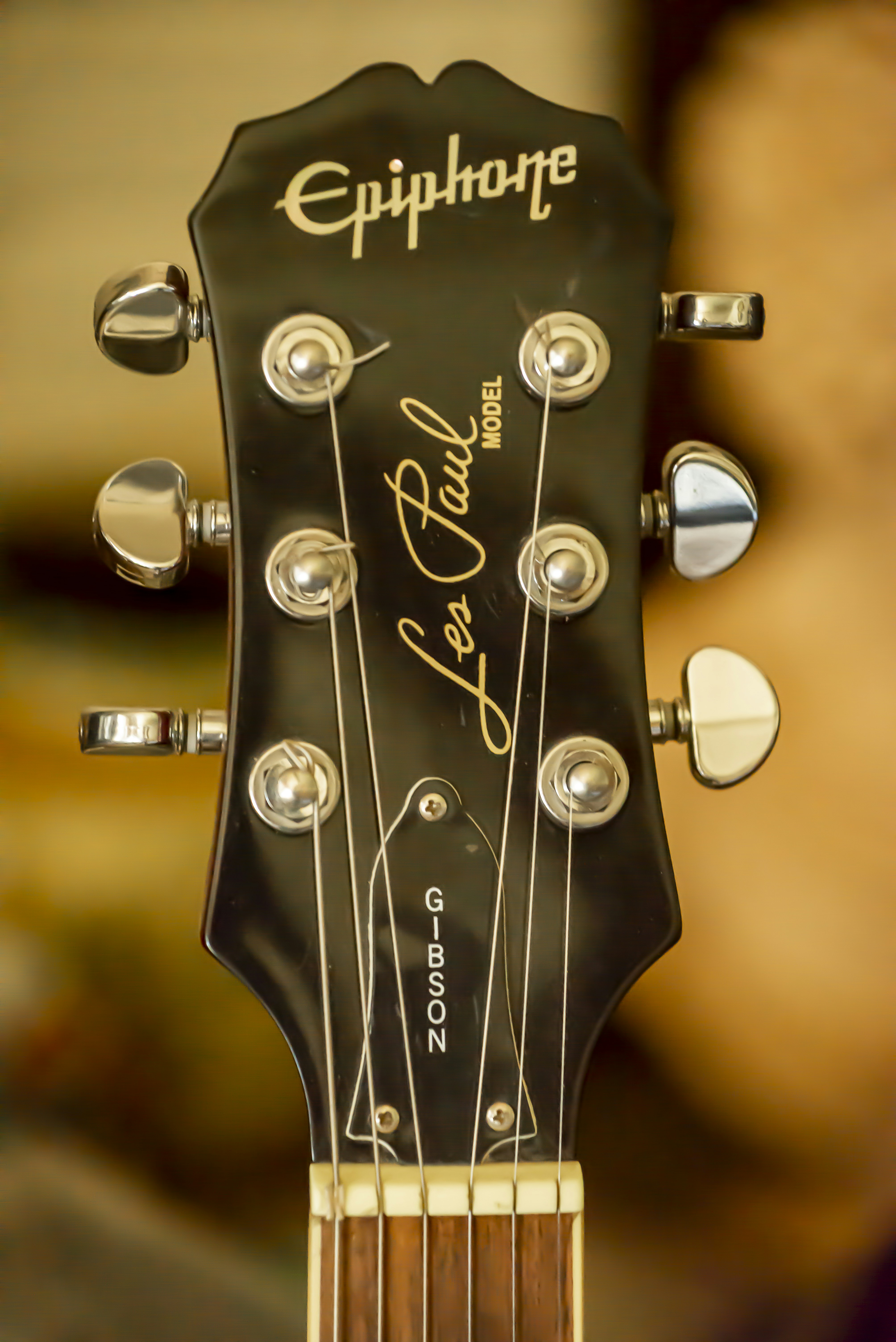 Close-up of an Epiphone Les Paul model headstock with tuning pegs and strings