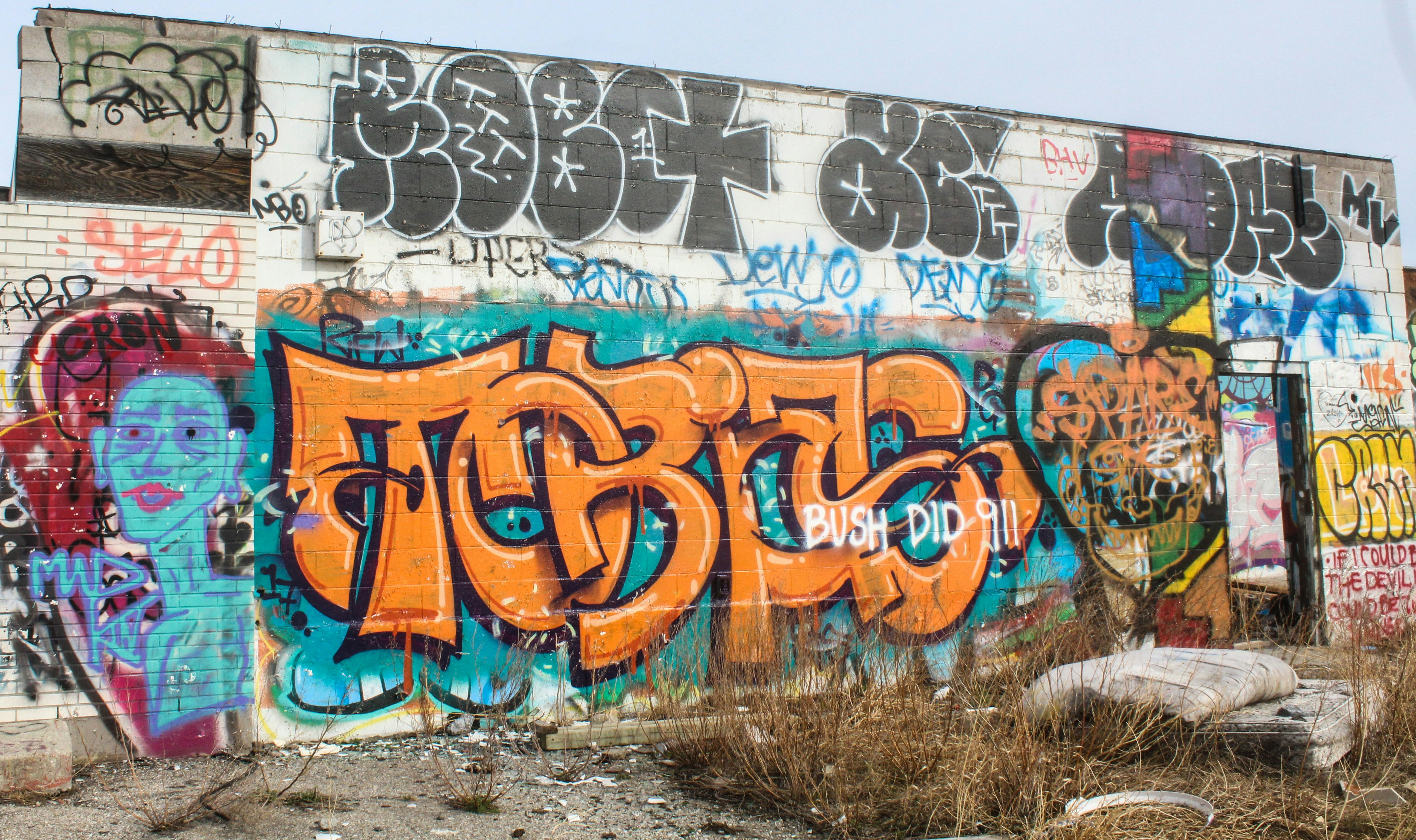 Urban Graffiti Mosaic: Centered Orange Tag Amid Ragged Wall Portraits